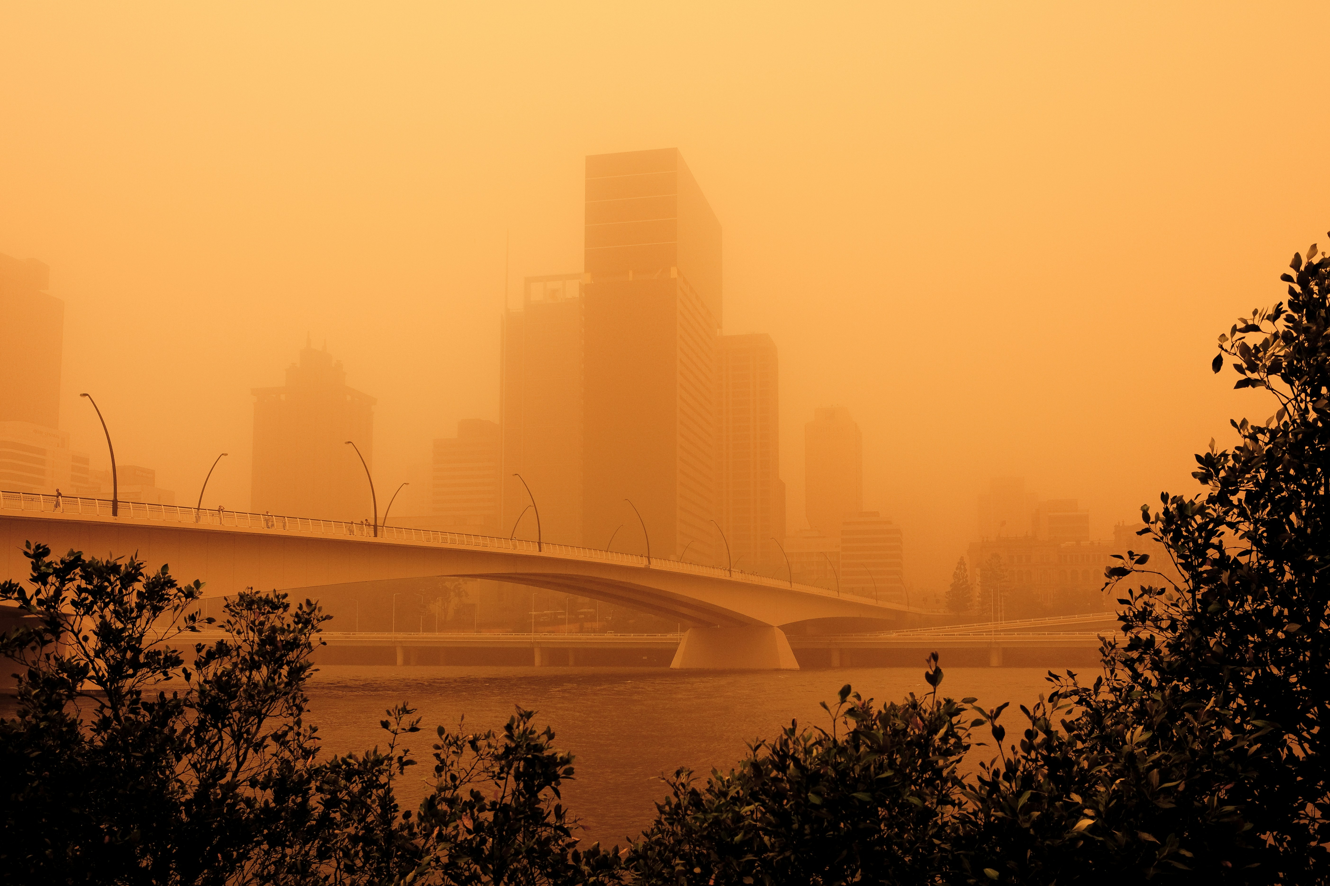 A dust storm hits Brisbane City, Australia in 2009. | City skyline obscured by a thick orange dust storm.