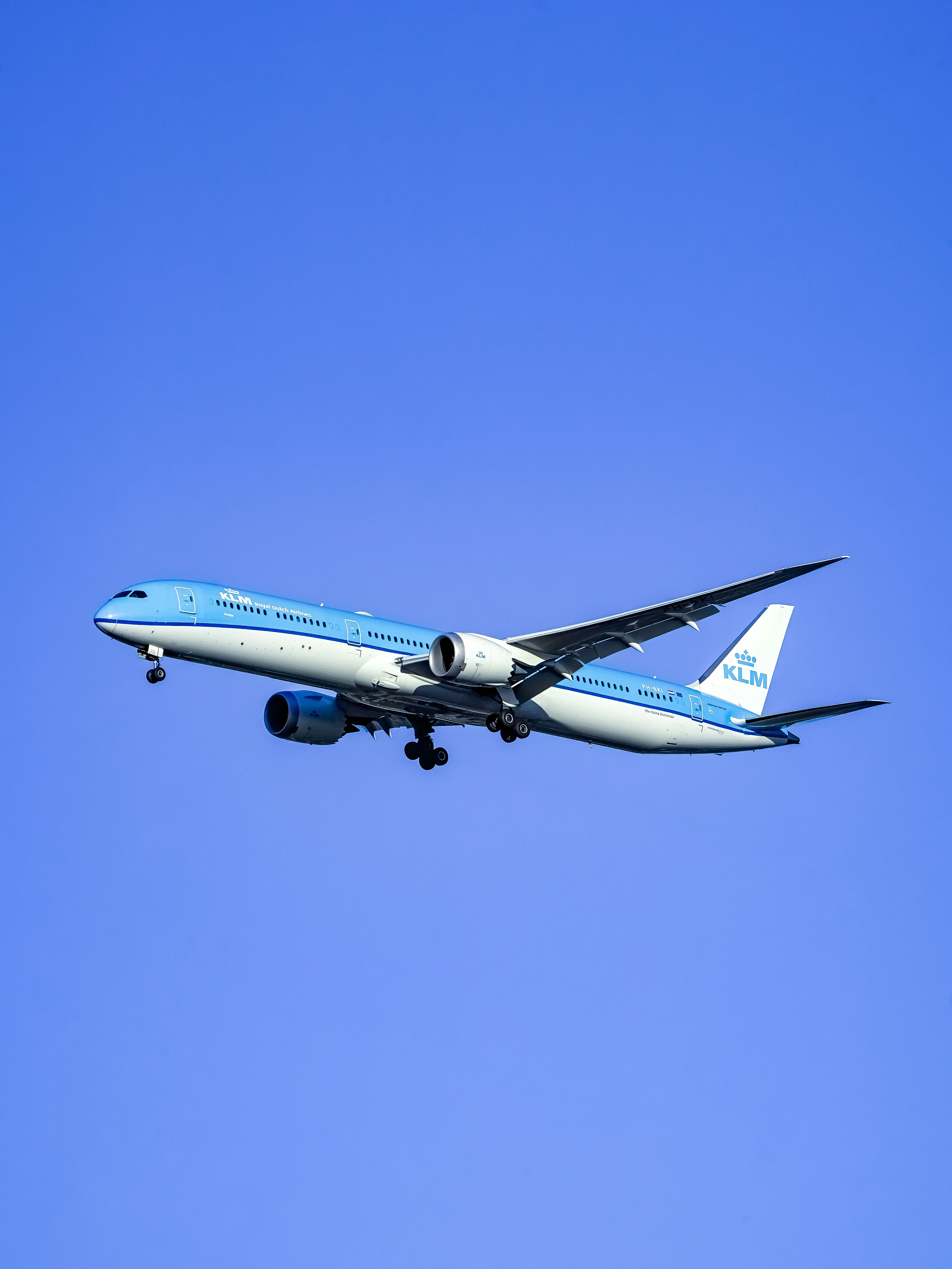 KLM airplane gracefully gliding through a clear blue sky, showcasing its sleek design and vibrant livery.