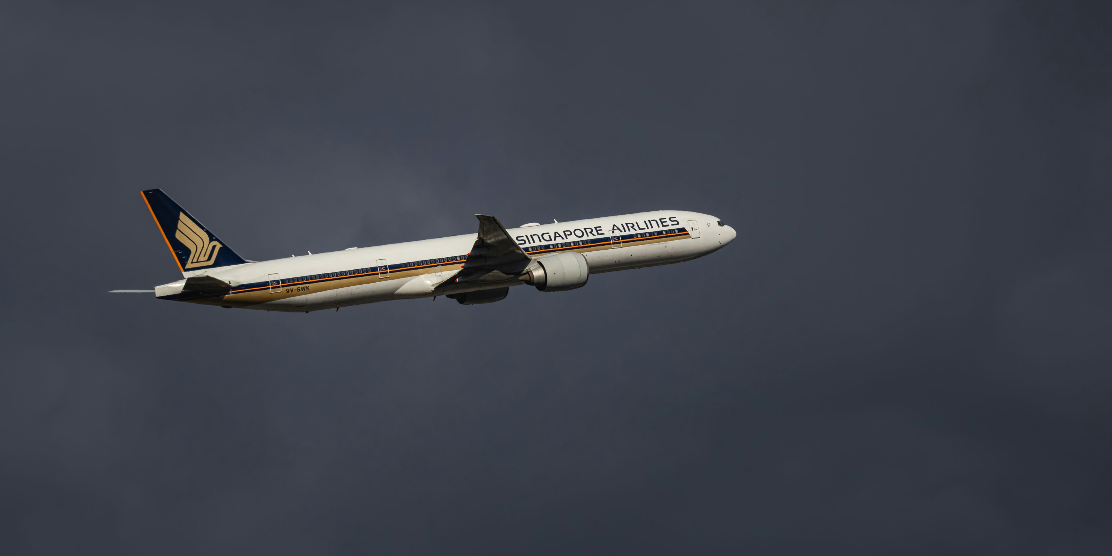Airplane flying against a dark, cloudy sky