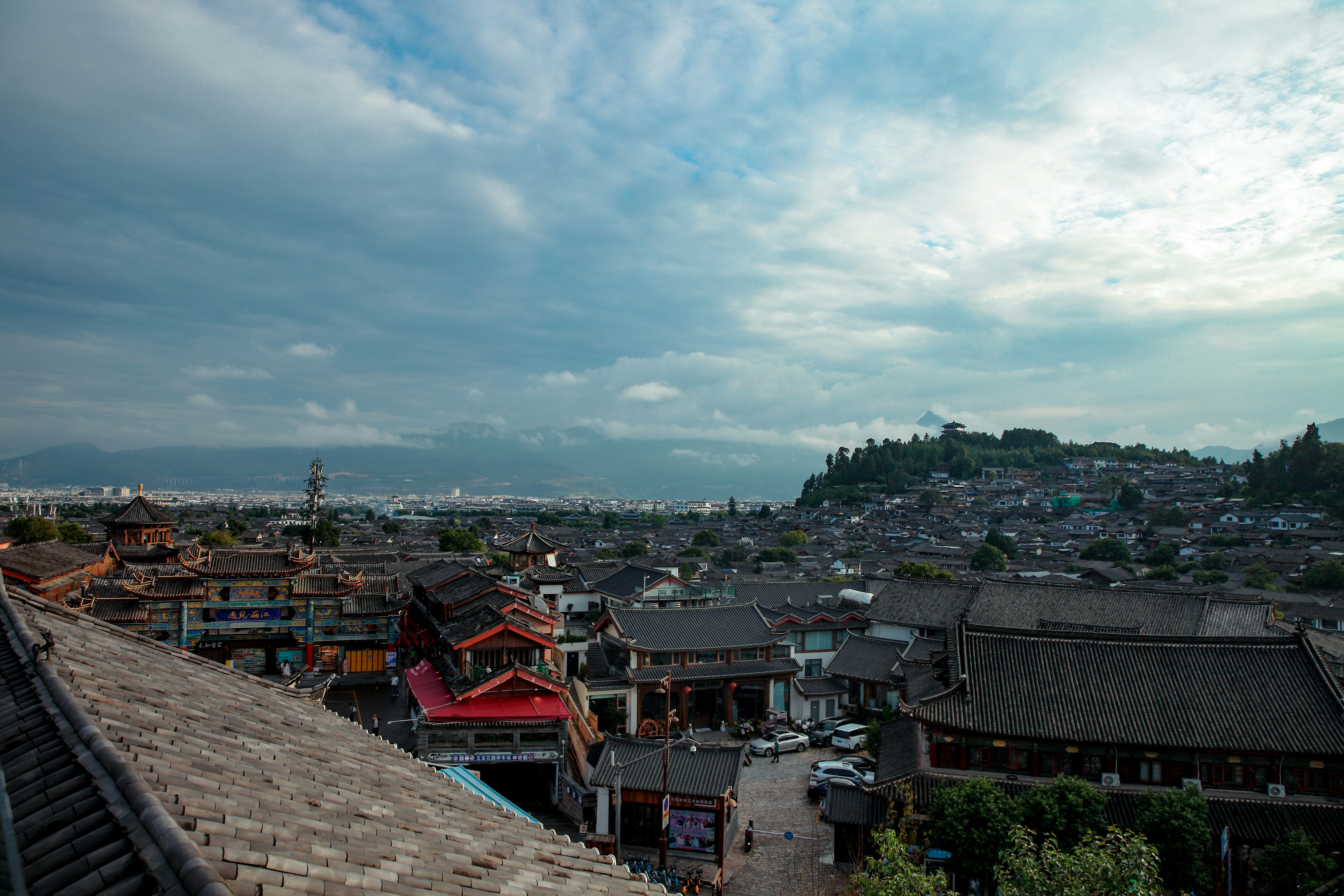 Vibrant rooftops of traditional architecture nestled against a mountainous backdrop under a dynamic sky.