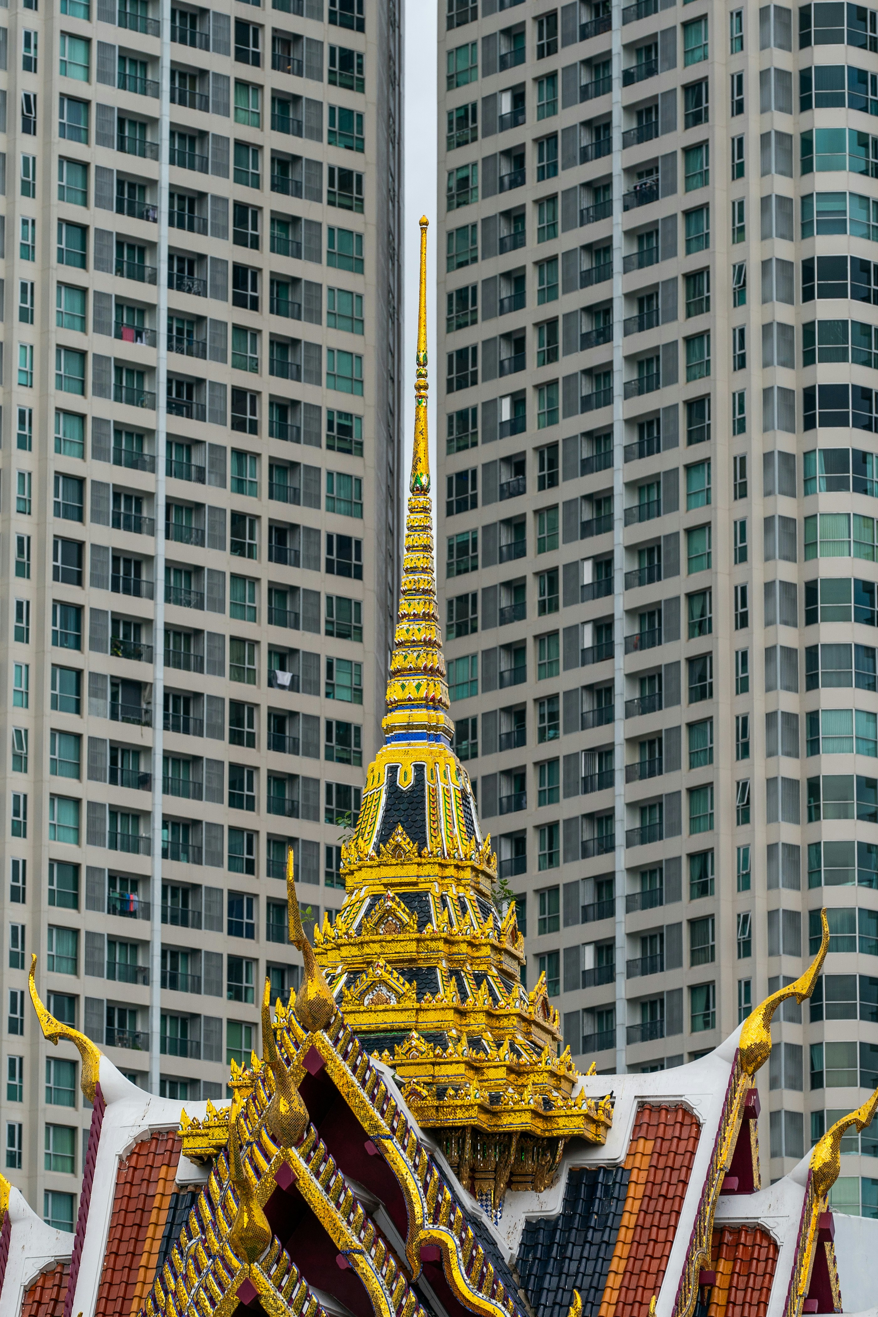 Ornate golden temple spire between modern buildings
