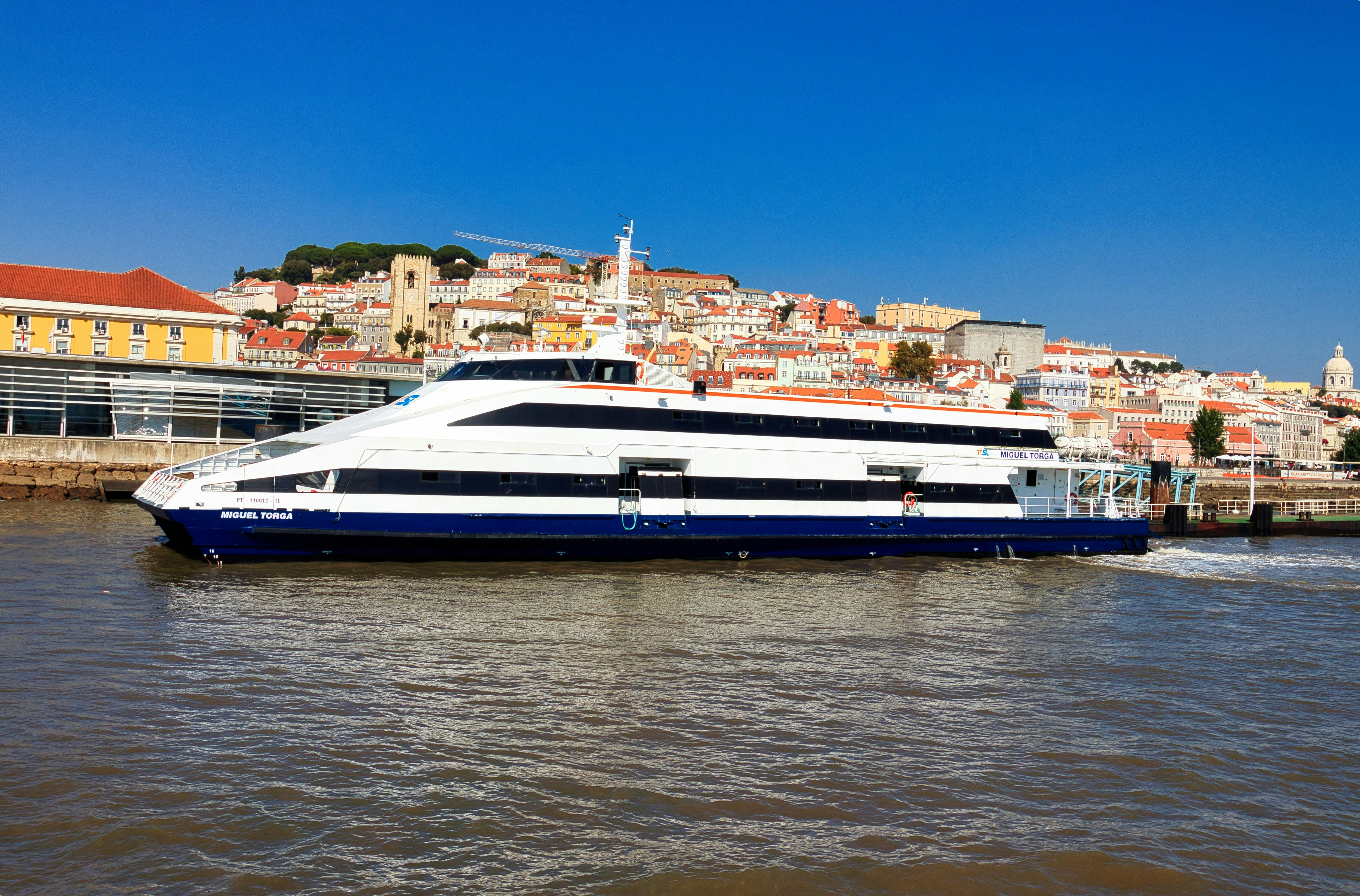 Ferry on the river at Lisbon | Modern ferry boat sailing on the water near buildings.