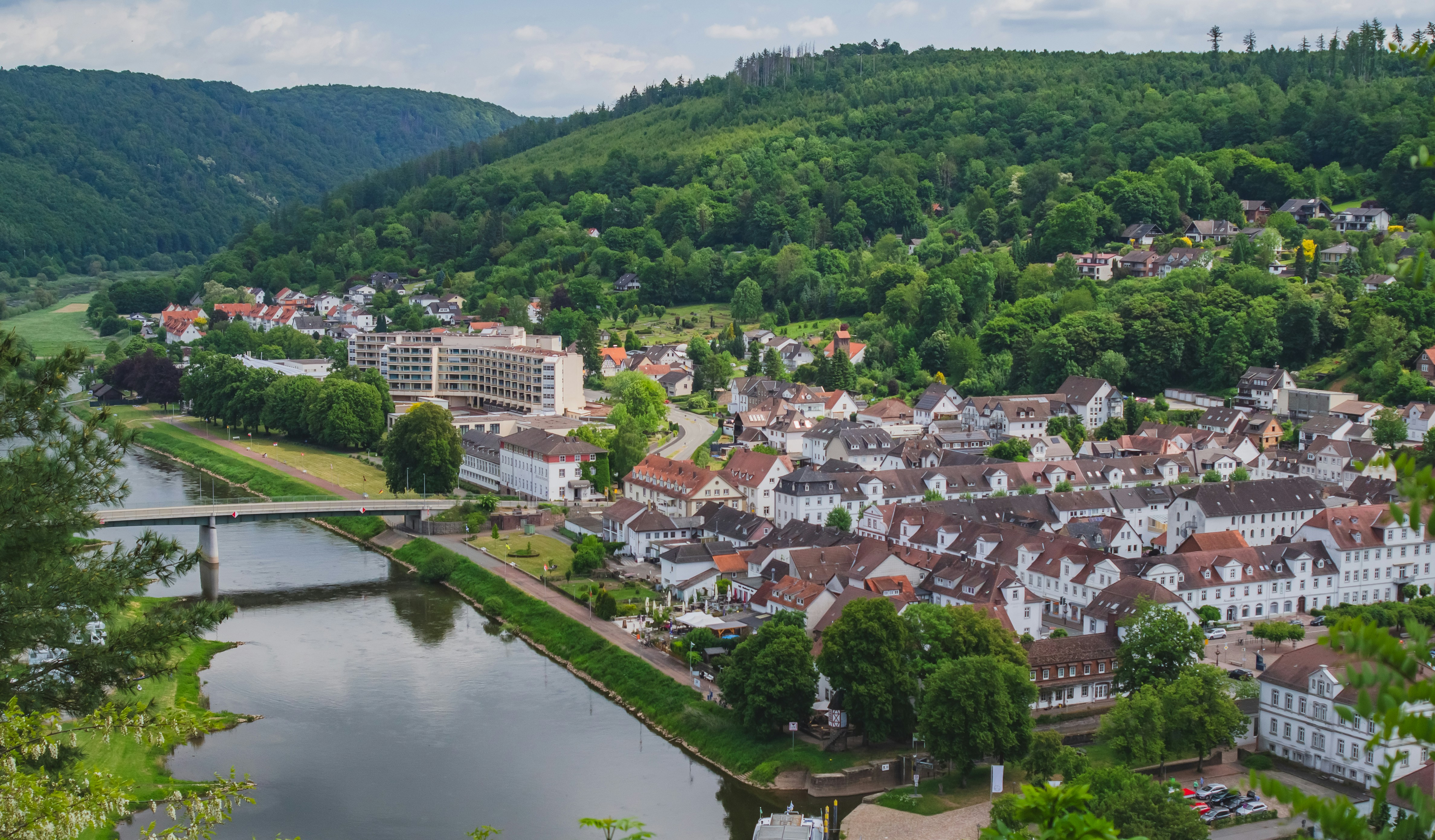 River flows through a green town nestled in hills.