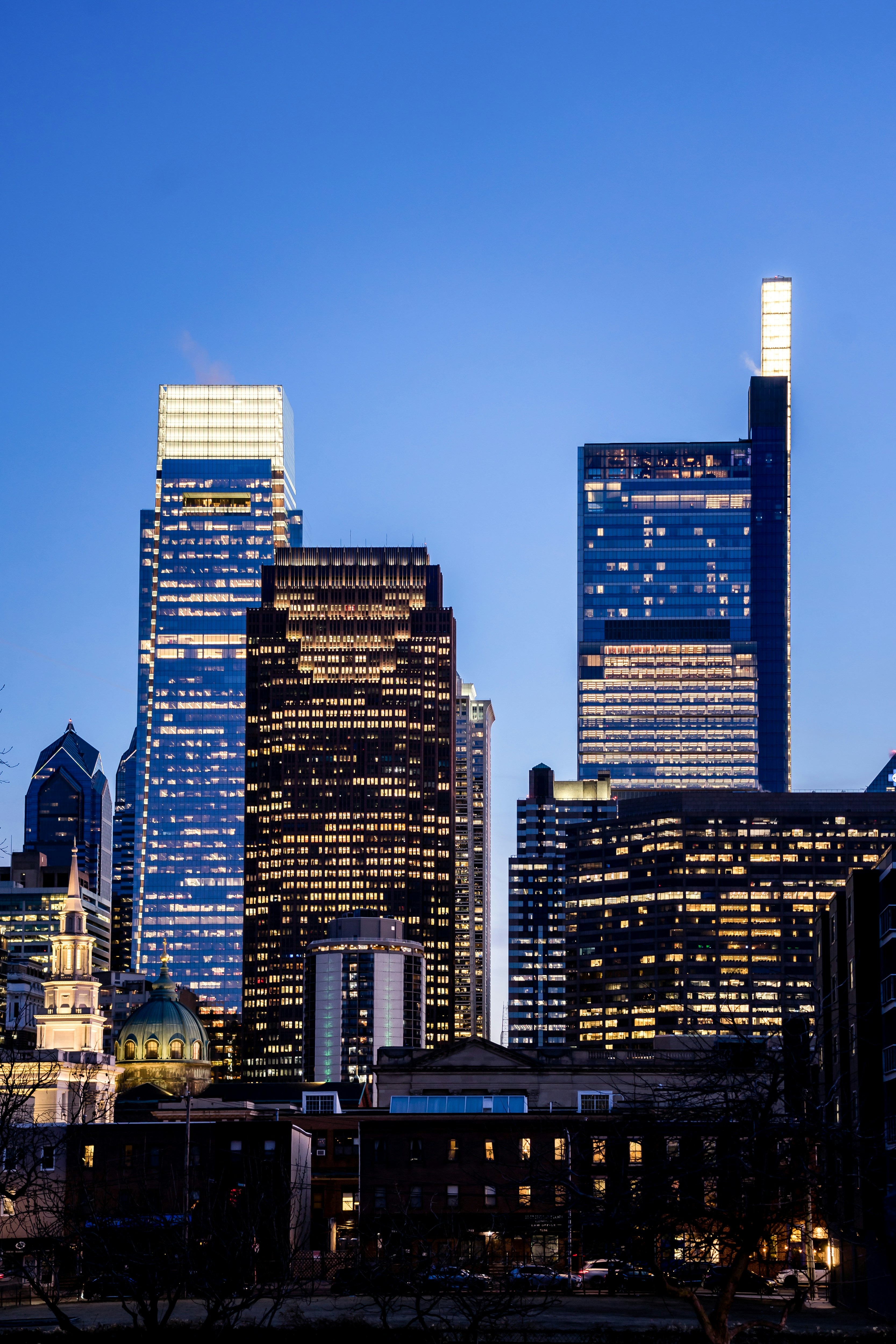 City skyline with illuminated skyscrapers at dusk.