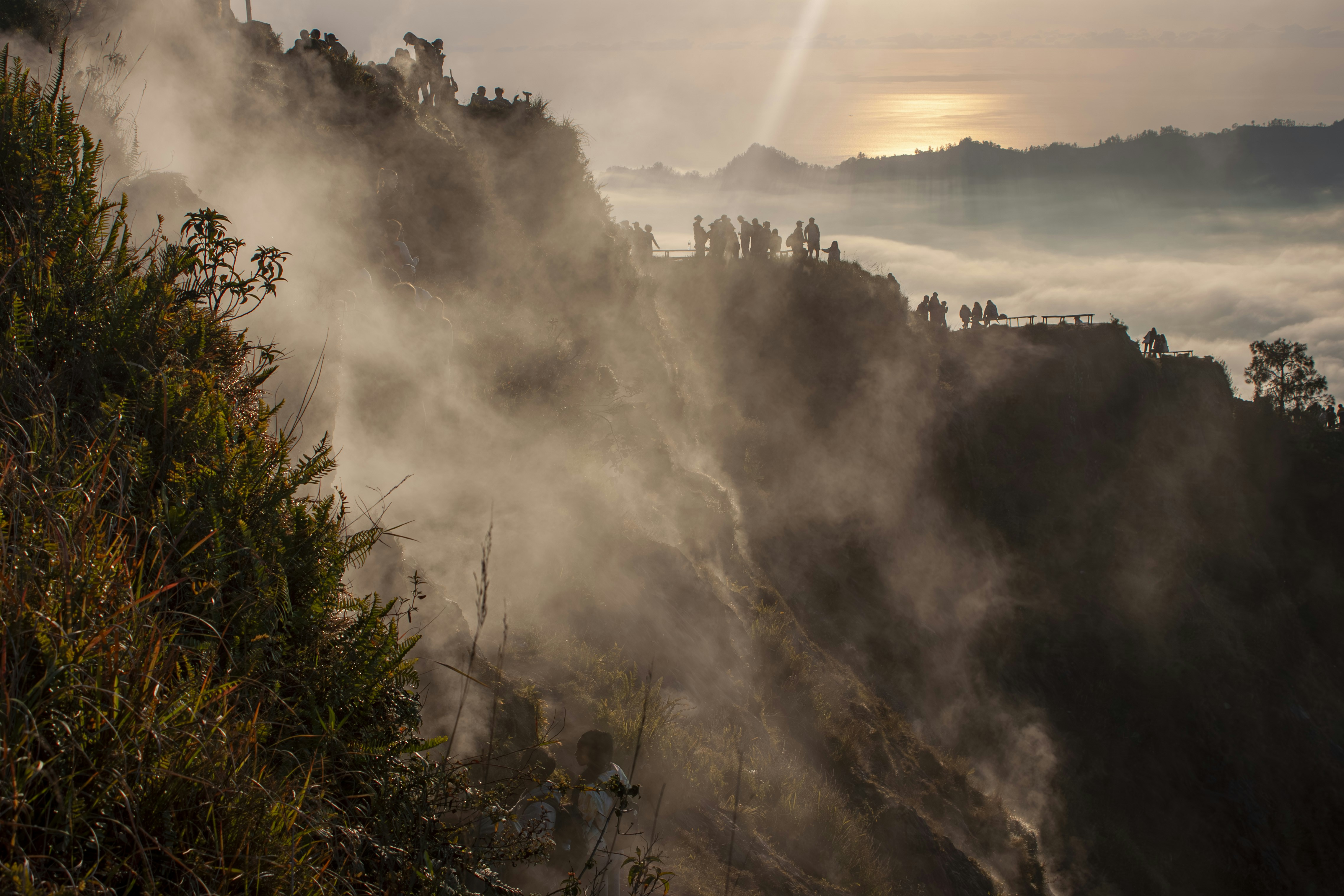 Misty volcanic landscape with people on a ridge at sunrise