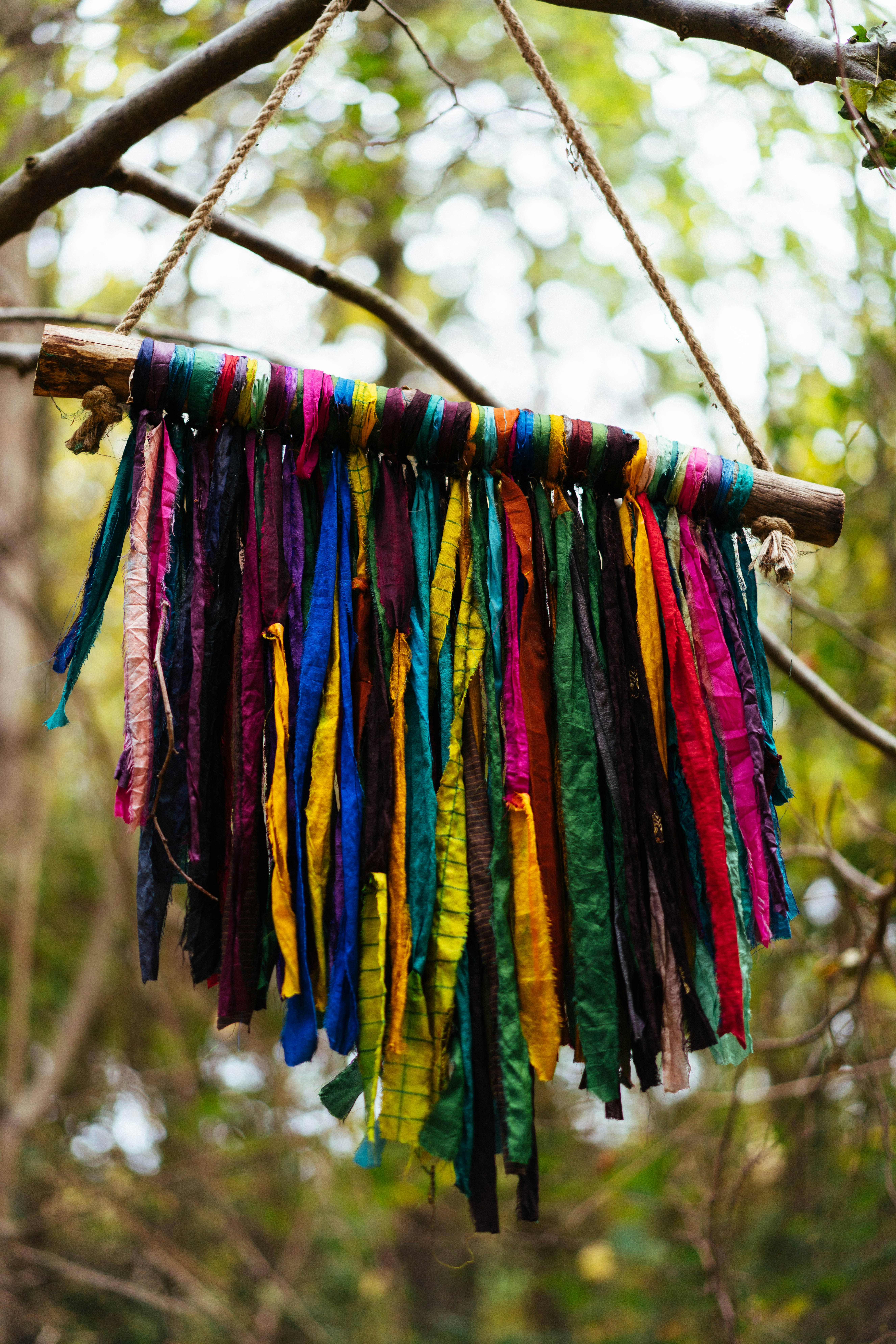 Colorful fabric strips hanging from a wooden branch