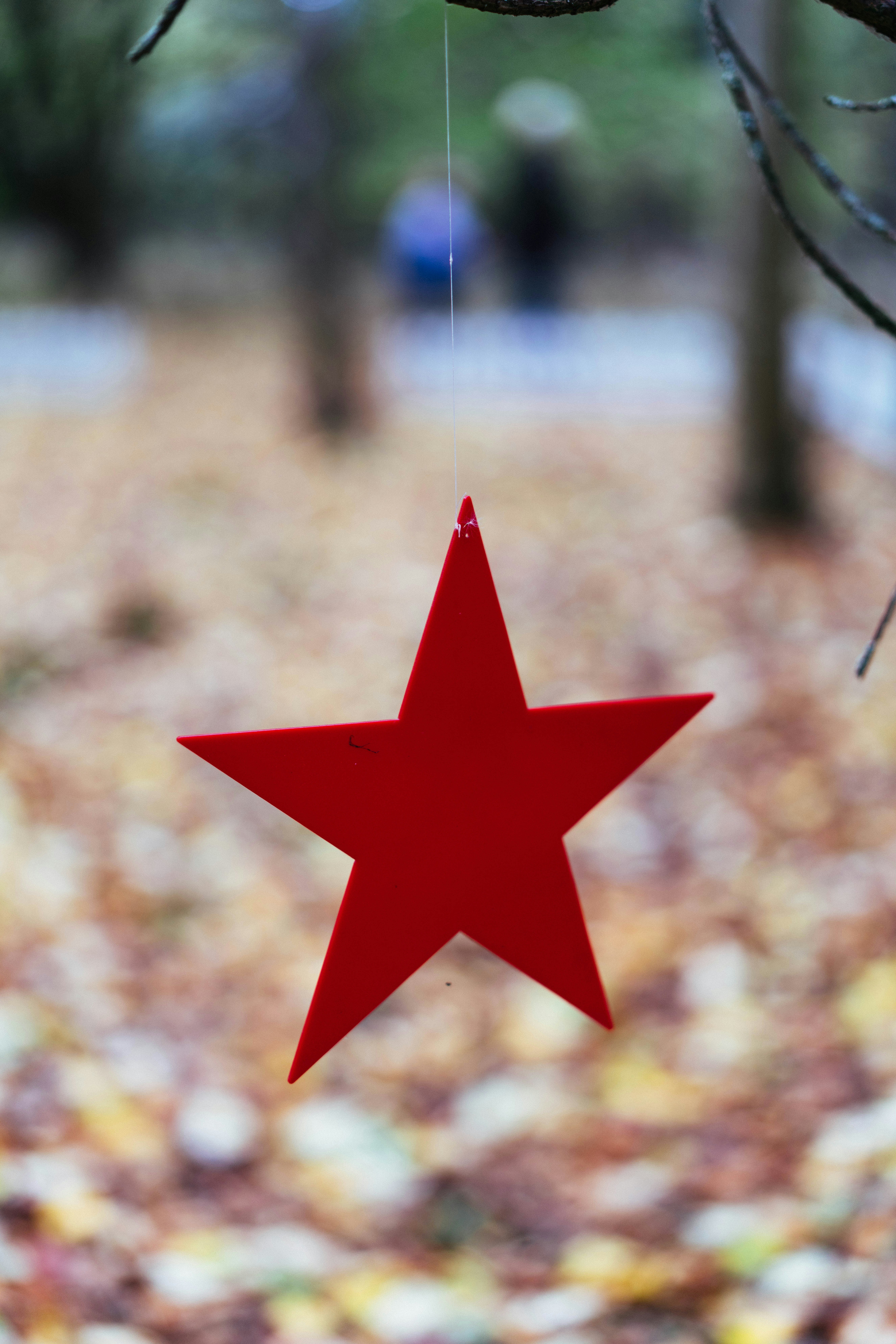 A red star decoration hangs outdoors in autumn.