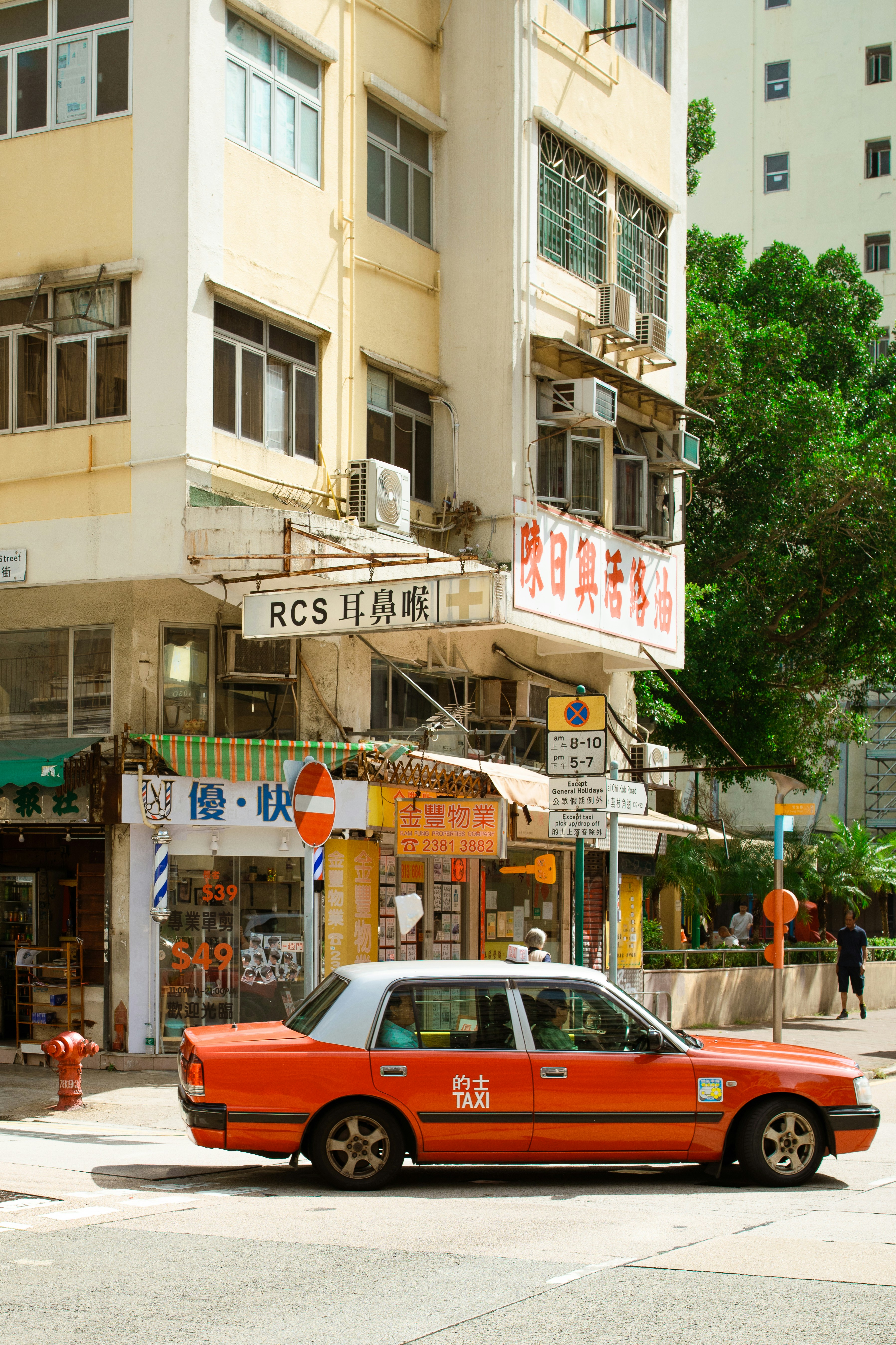 Orange taxi drives past buildings in city