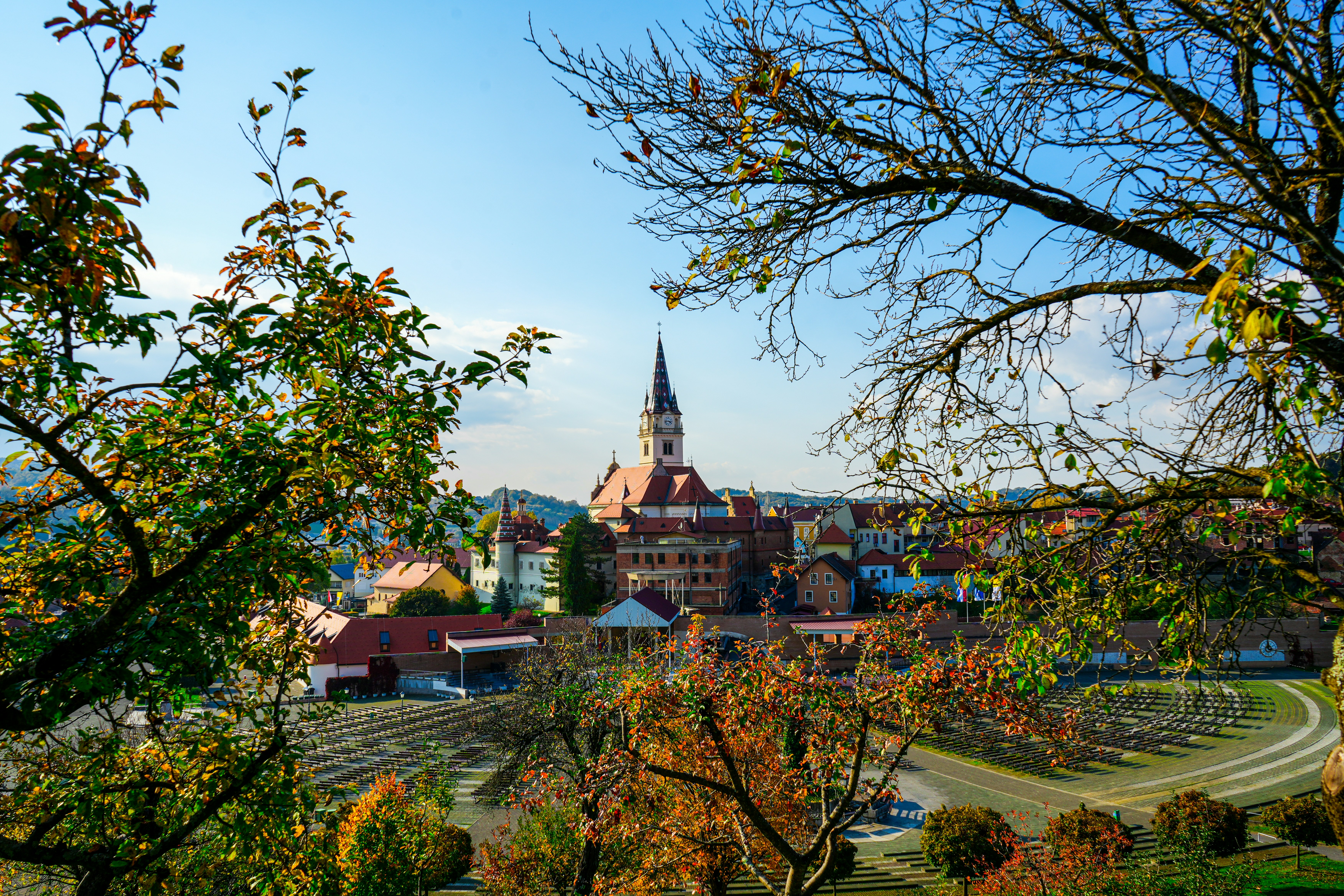 Village with church steeple framed by autumn trees.