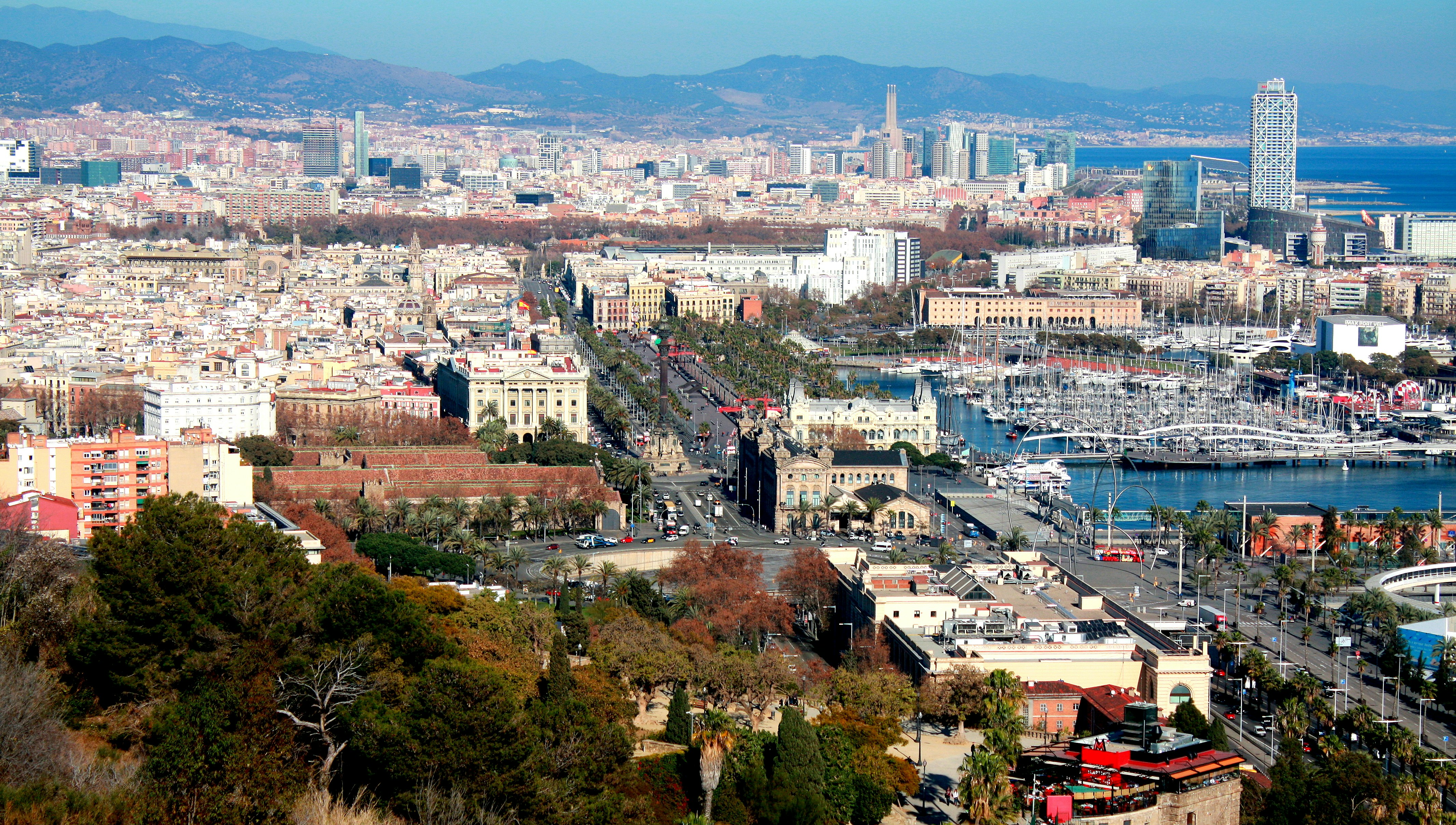 Barcelona cityscape view. | Panoramic view of a bustling city with a harbor.