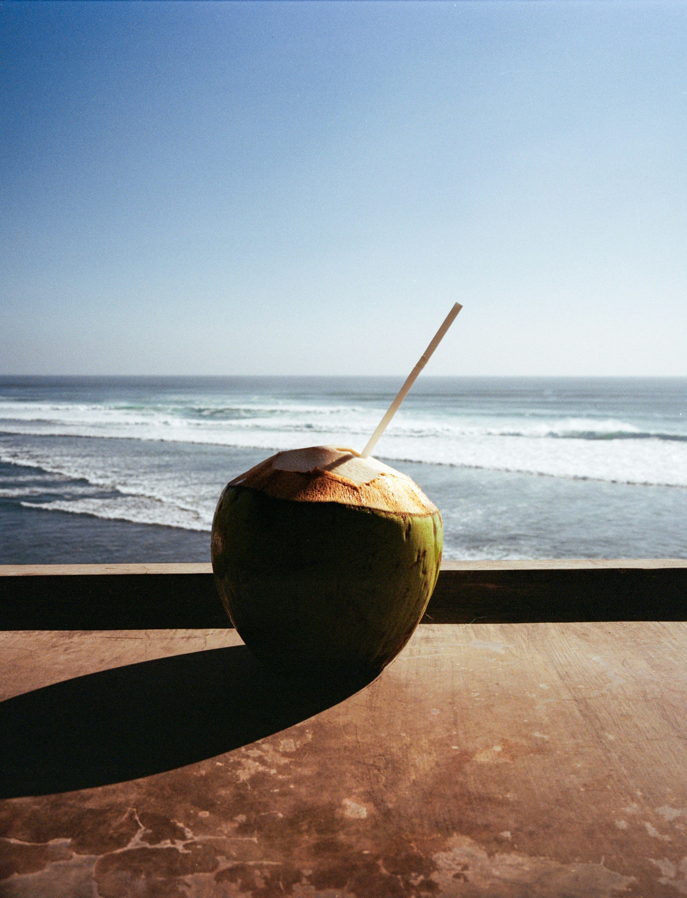 Kodak Gold 200 🎞️ | Fresh coconut with straw on beach overlooking ocean
