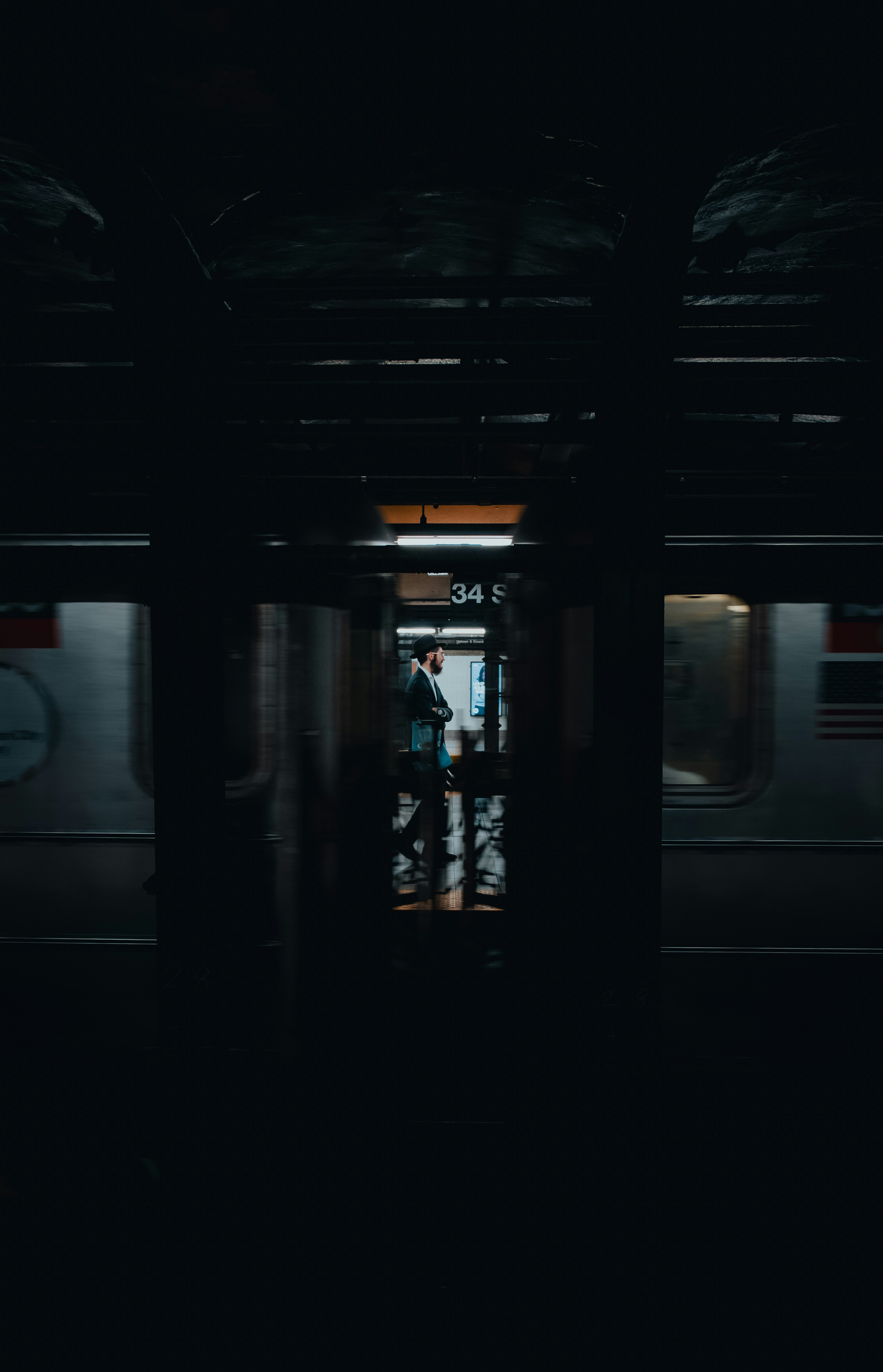 Man standing in subway doorway with train behind him.