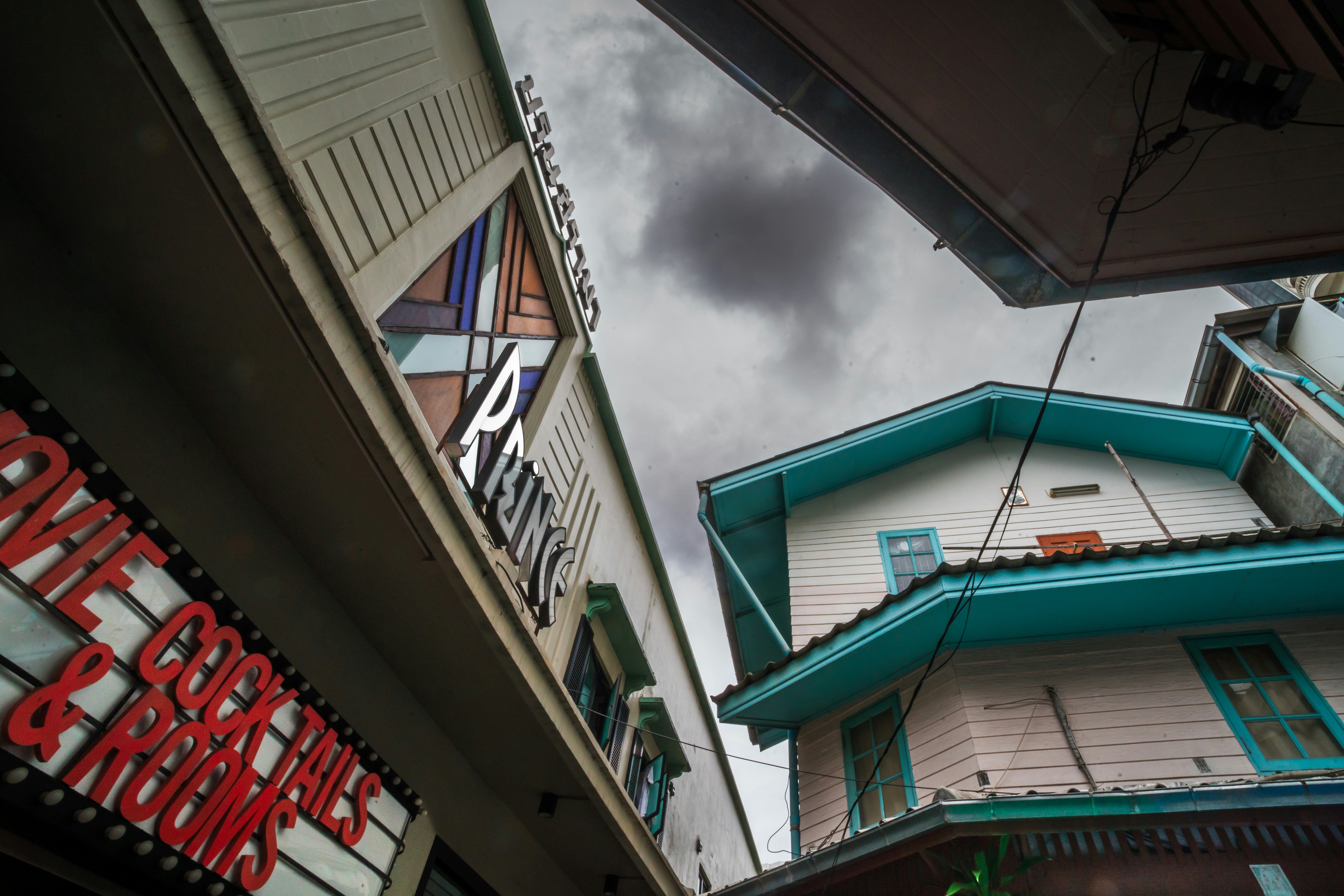 Buildings with neon signs under cloudy sky