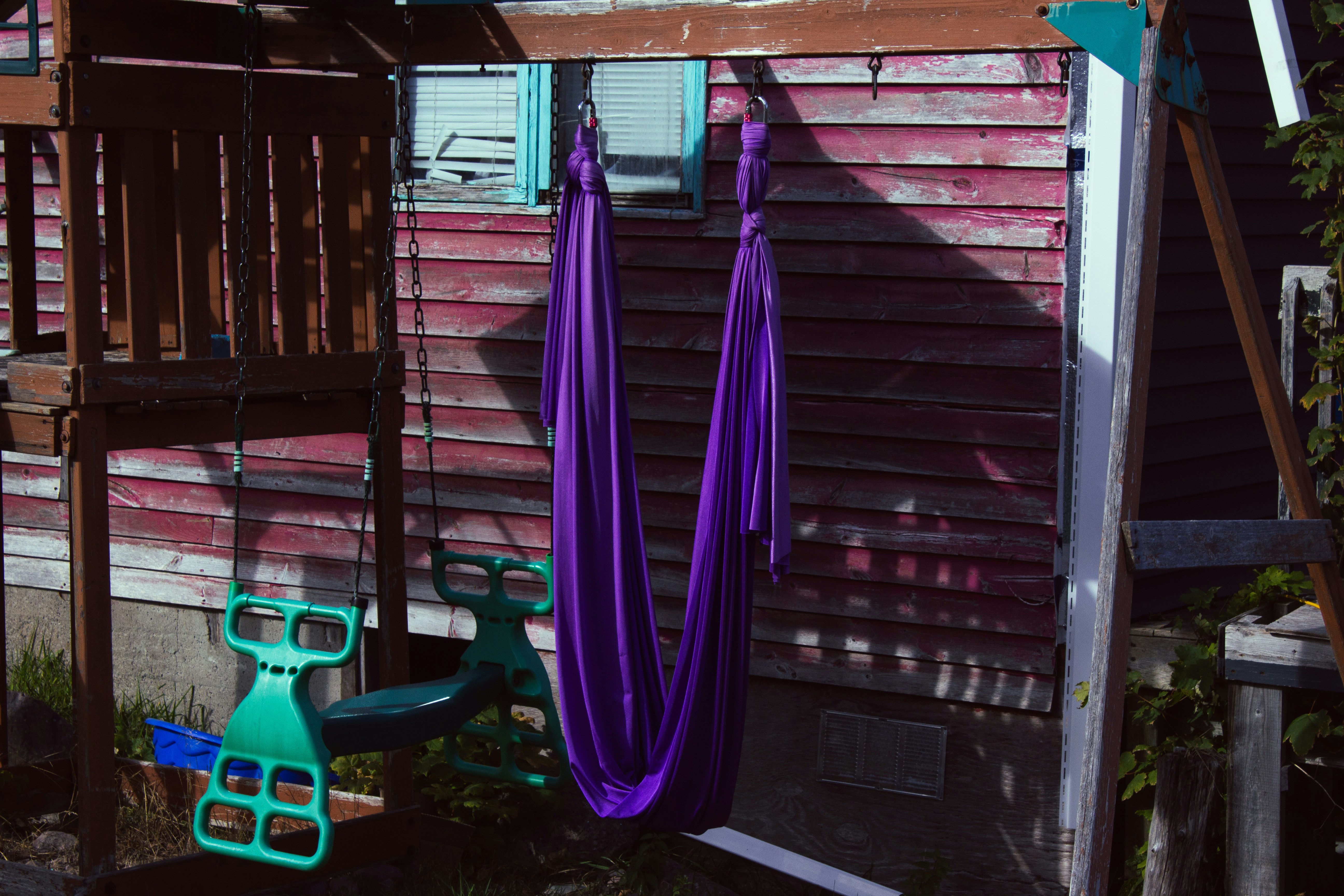 Purple aerial yoga swing hangs on wooden structure