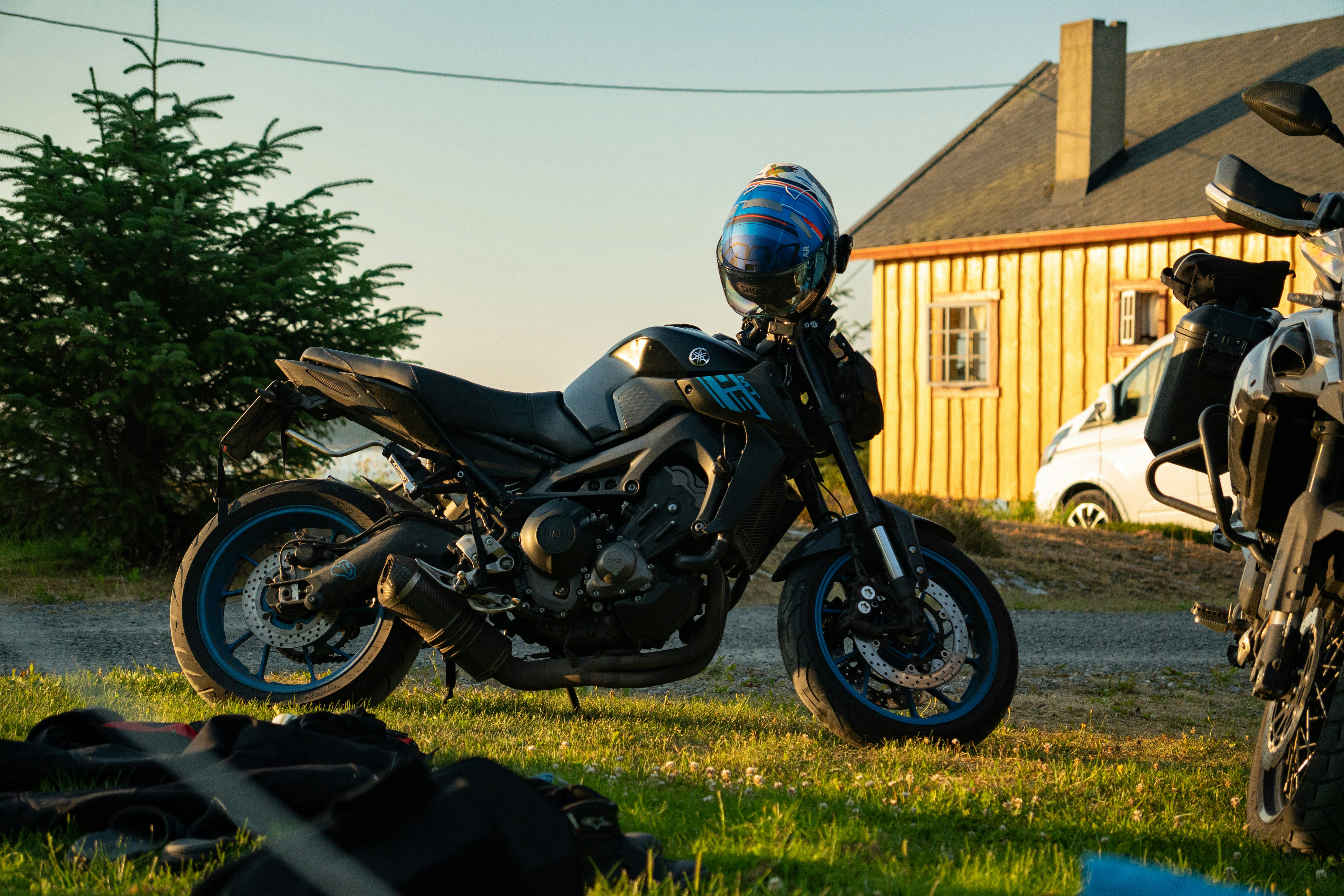 Sunlit Frame: A Modern Streetbike Resting by a Rustic Cottage