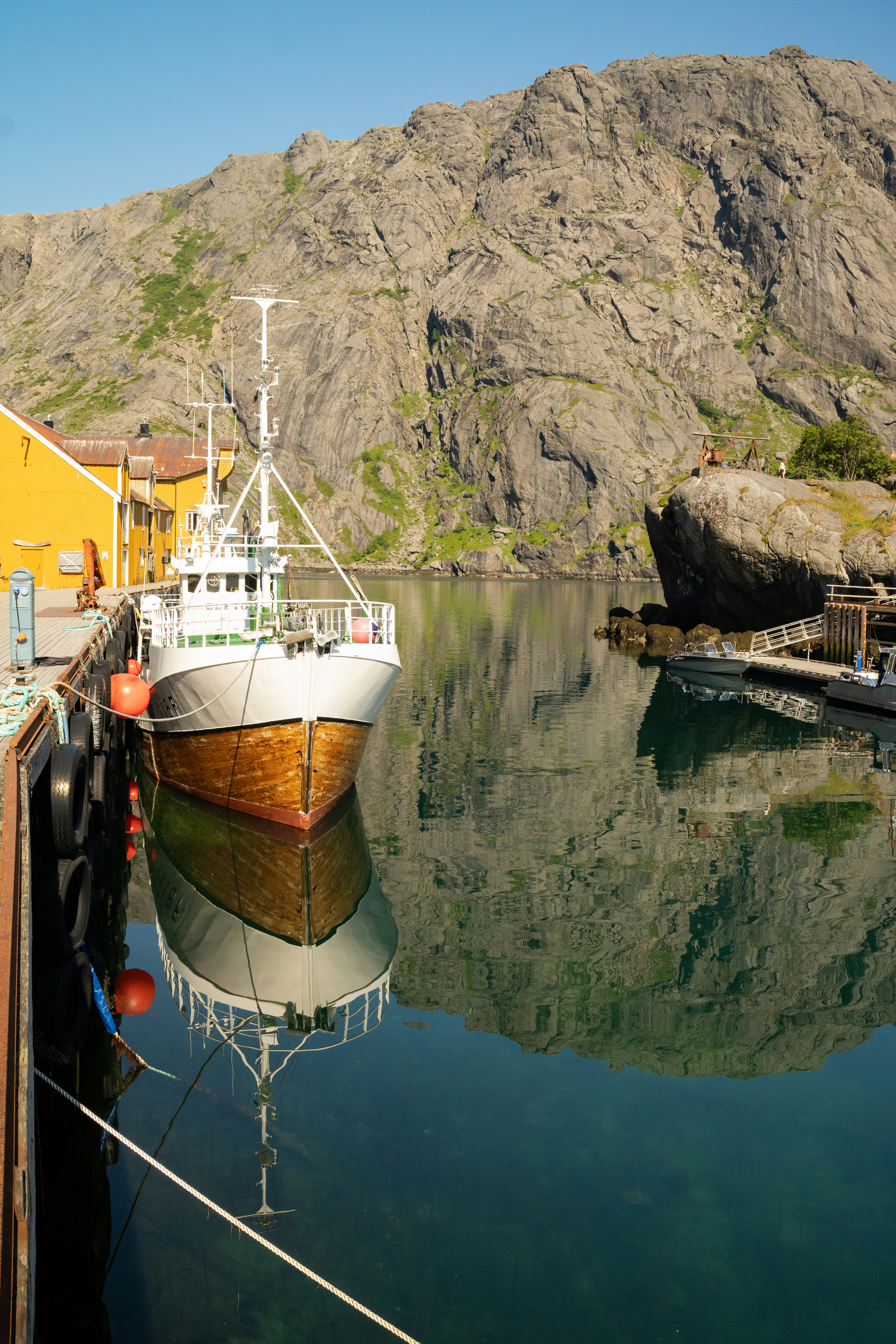 A white fishing boat docked next to a yellow building.