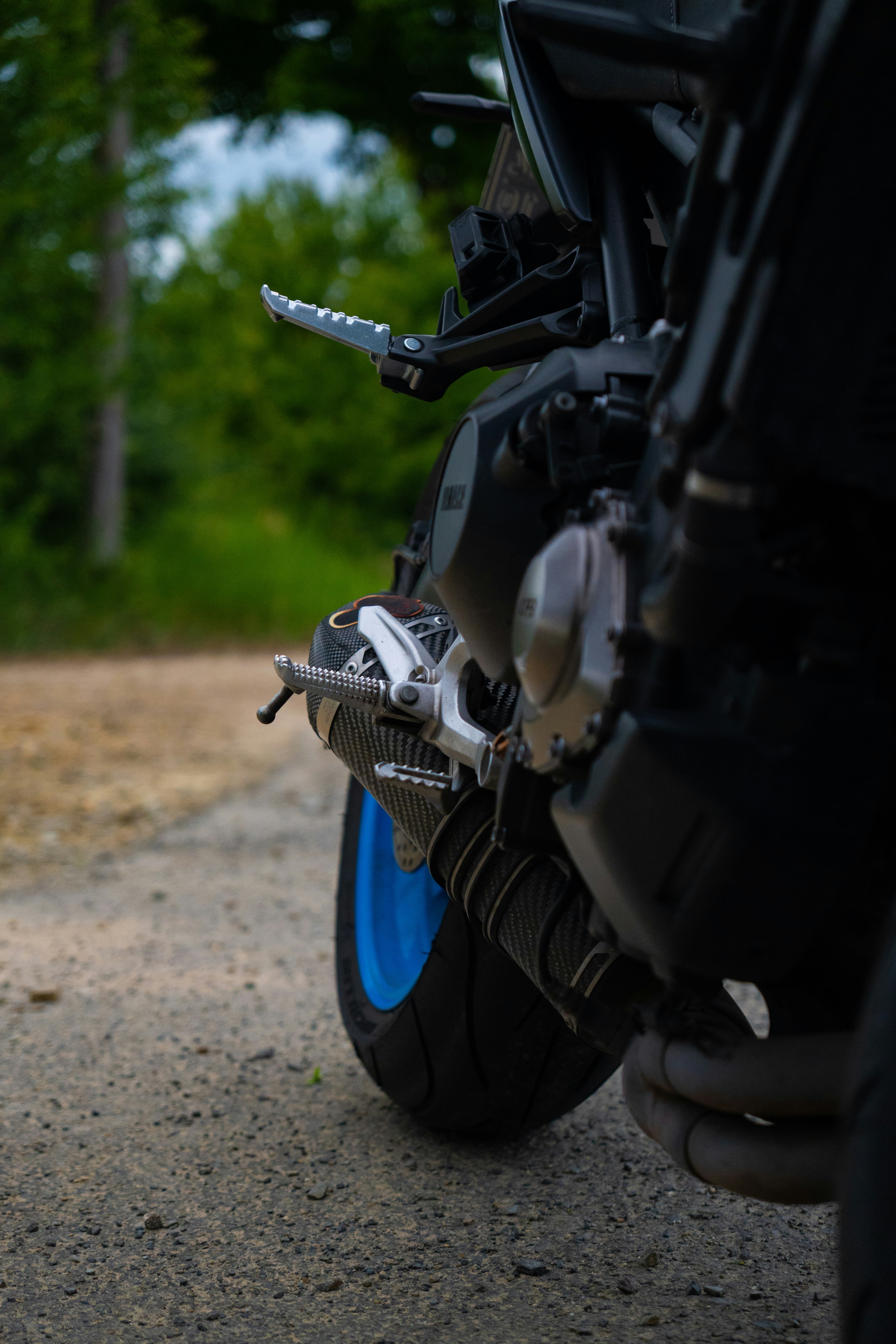 Close-Up on a Streetbike’s Heart: Metallic Footpeg and a Blue Rim