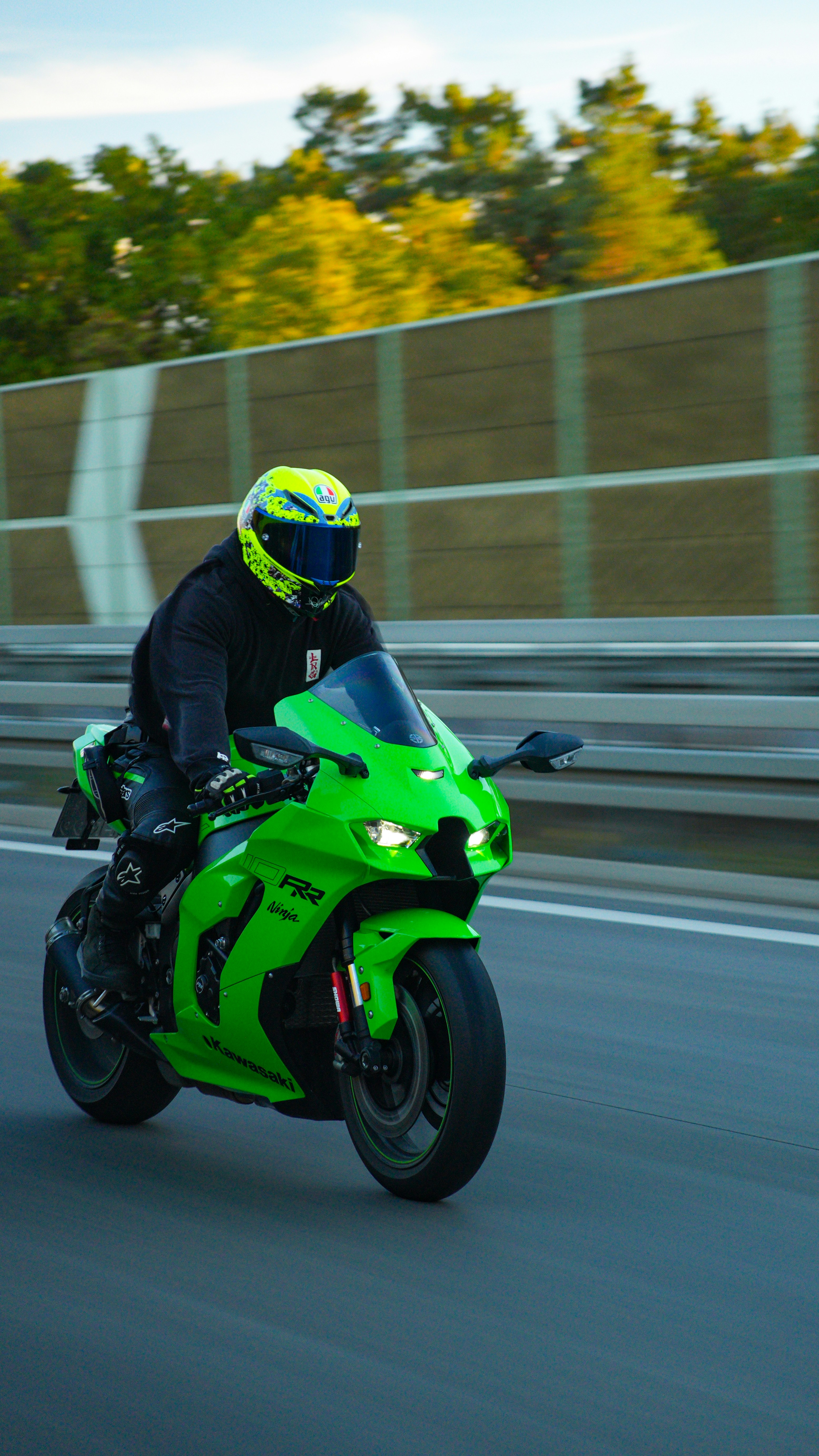 A person riding a bright green motorcycle on a highway.