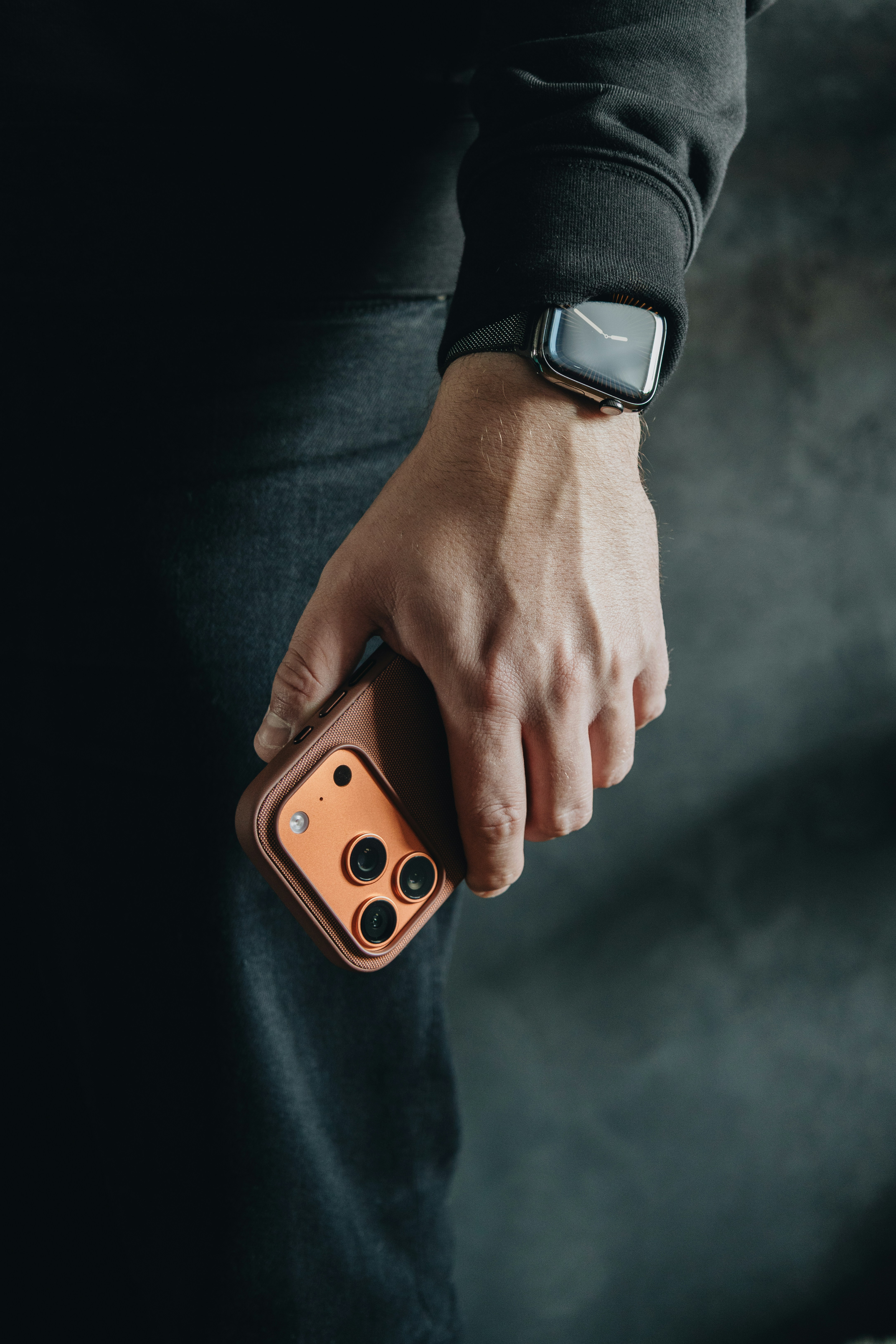 Holding an iPhone 17 Pro in Cosmic Orange color with TechWoven Siena case. | Person holding a smartphone with a camera lens