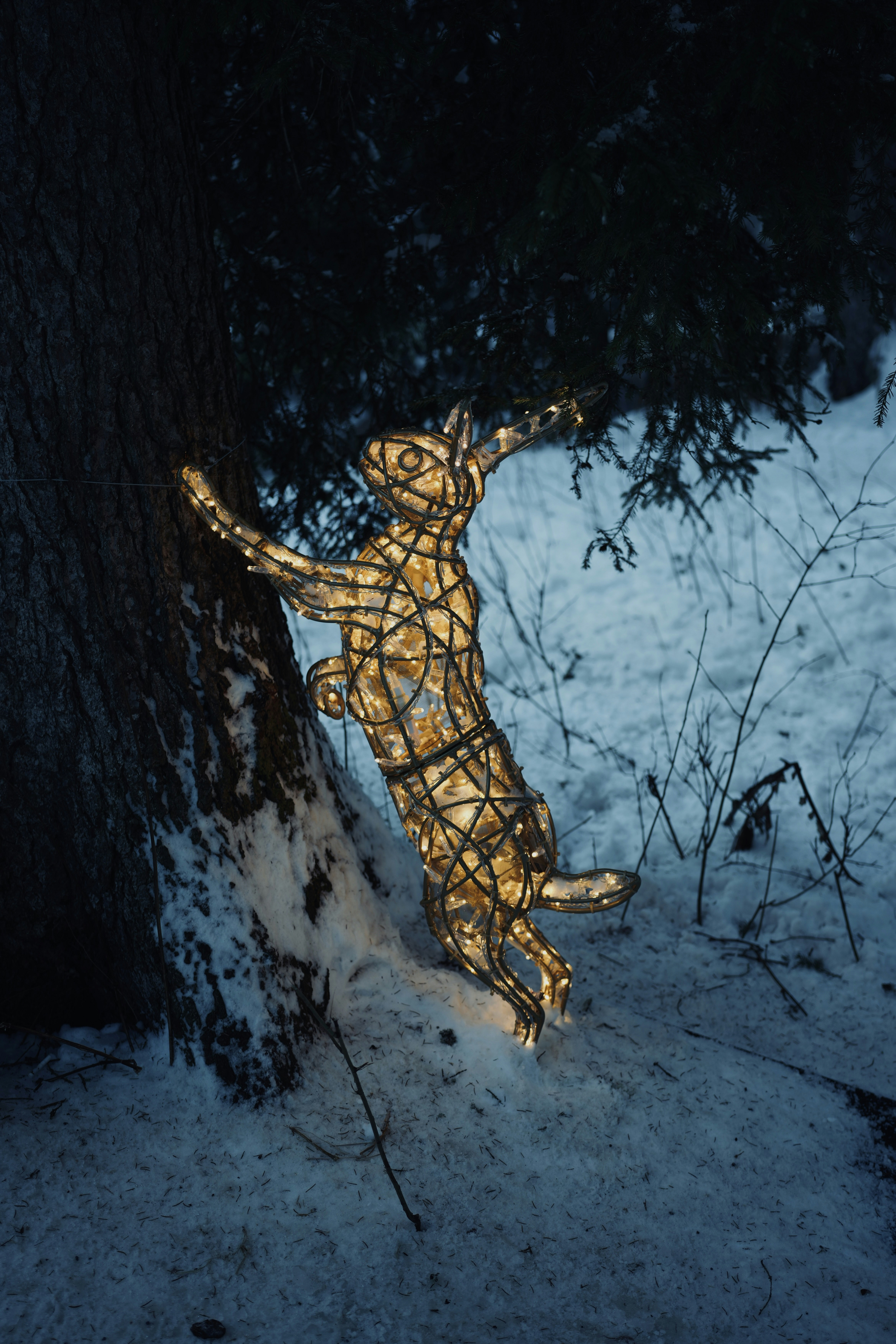 Luminous Wire-Reindeer Clinging to a Snow-Dusted Pine at Dusk