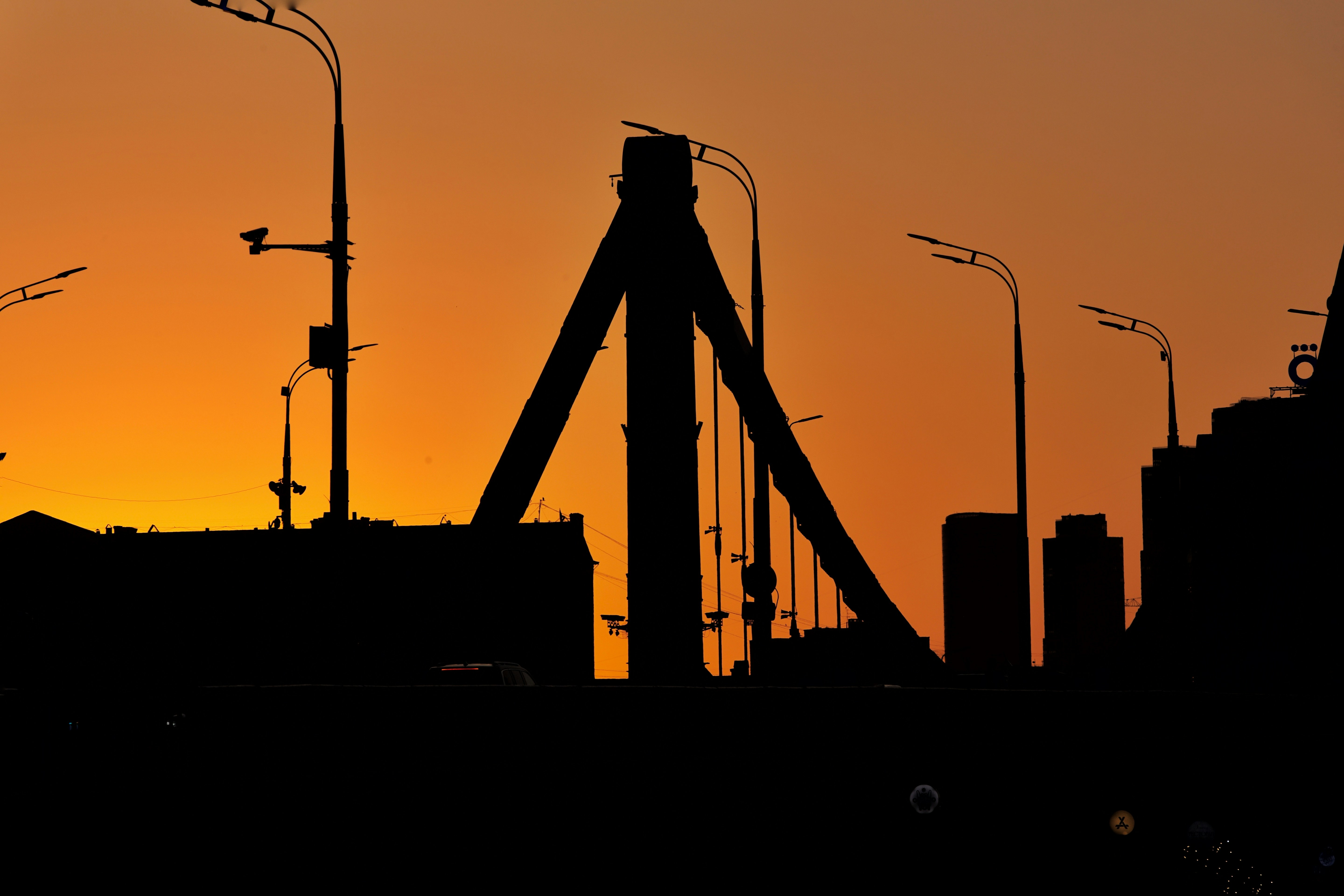 Silhouette of a bridge against an orange sunset sky