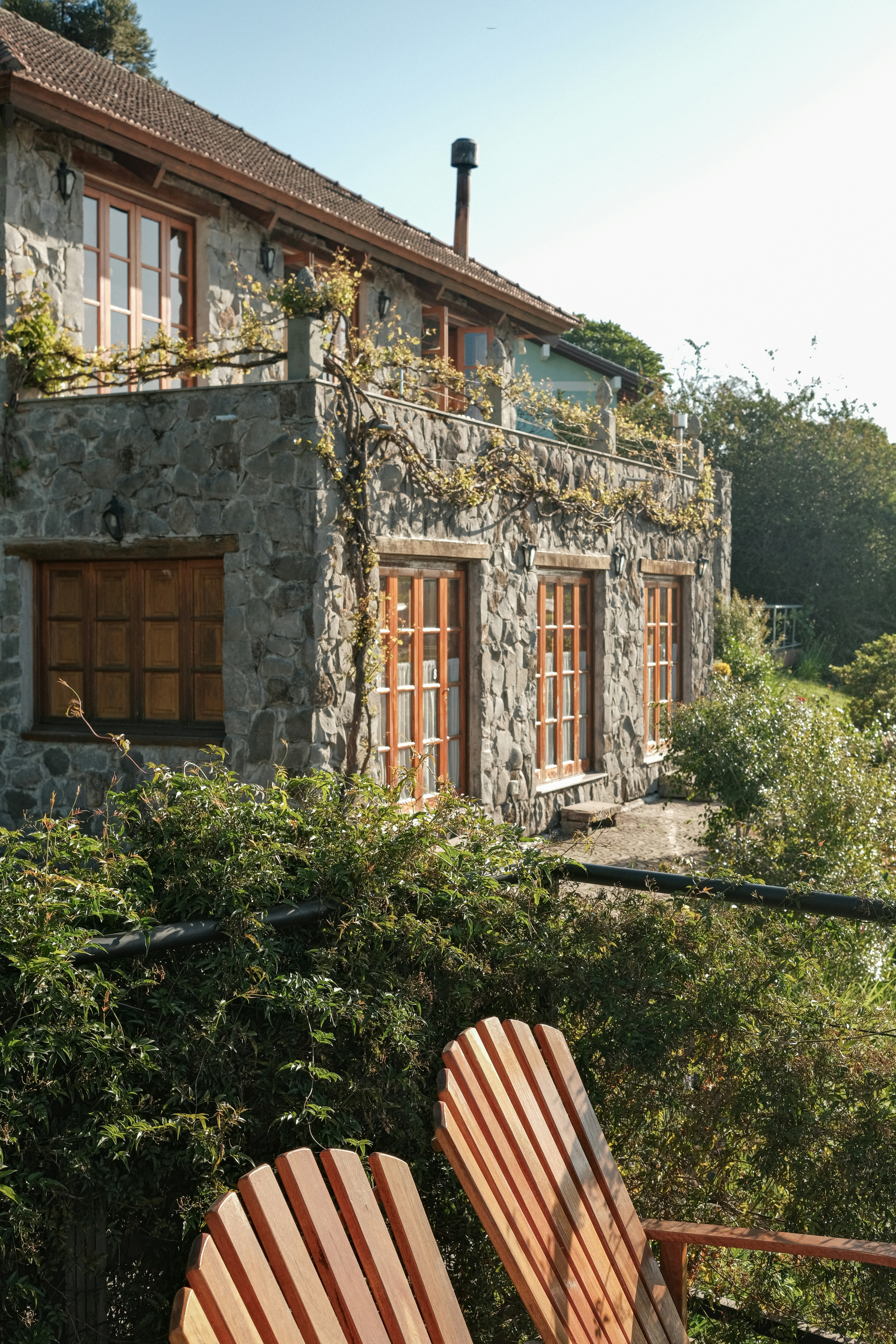 Fotografia para Pousada Borguetto, Bento Gonçalves, Serra Gaúcha. | Stone house with wooden windows and lush greenery