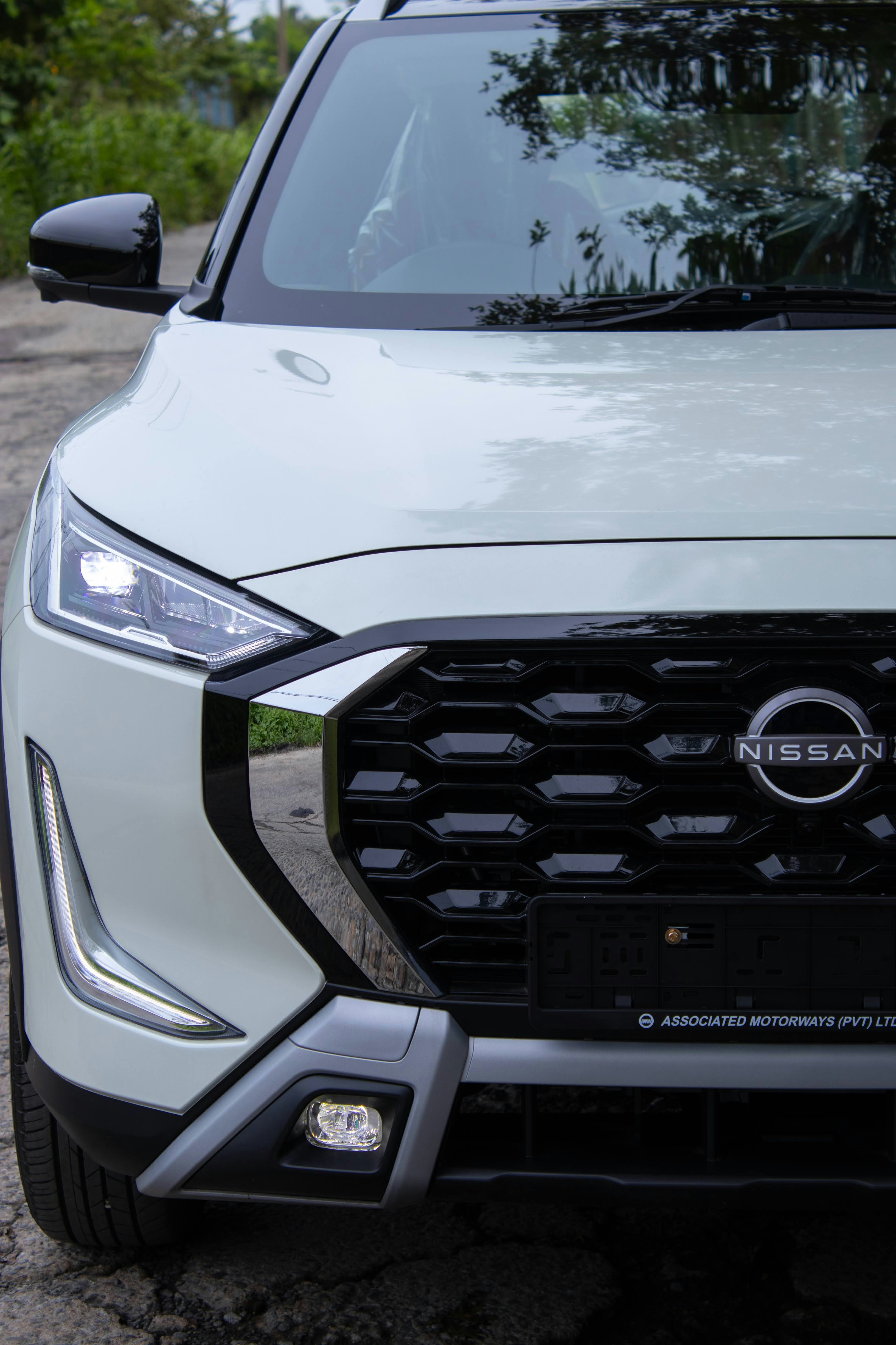 Close-up of a Nissan vehicle's front grille and headlights, showcasing its sleek design and modern aesthetics.
