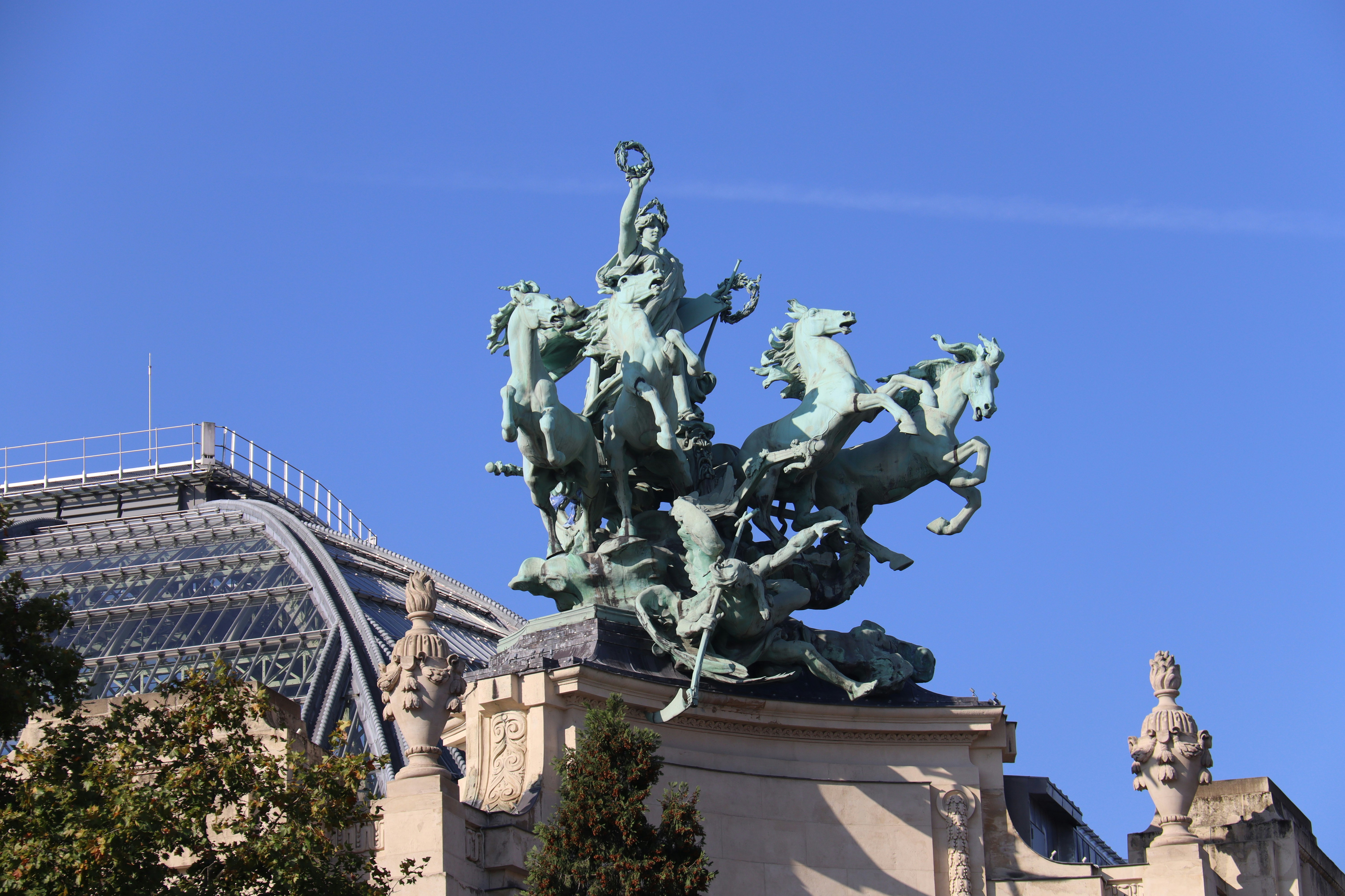 Bronze sculpture of horses and figures against blue sky