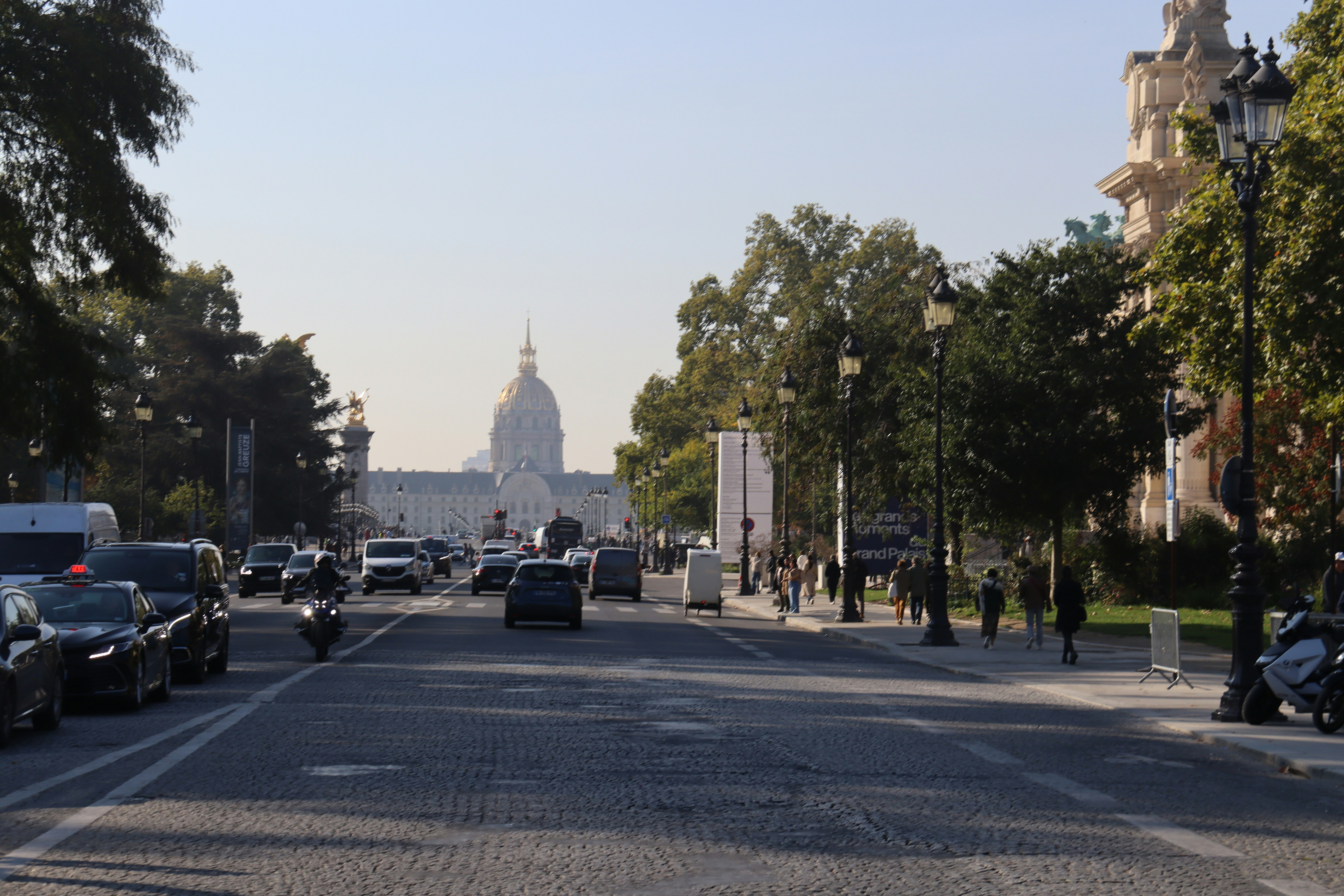 Cars driving on a wide street towards a dome building.