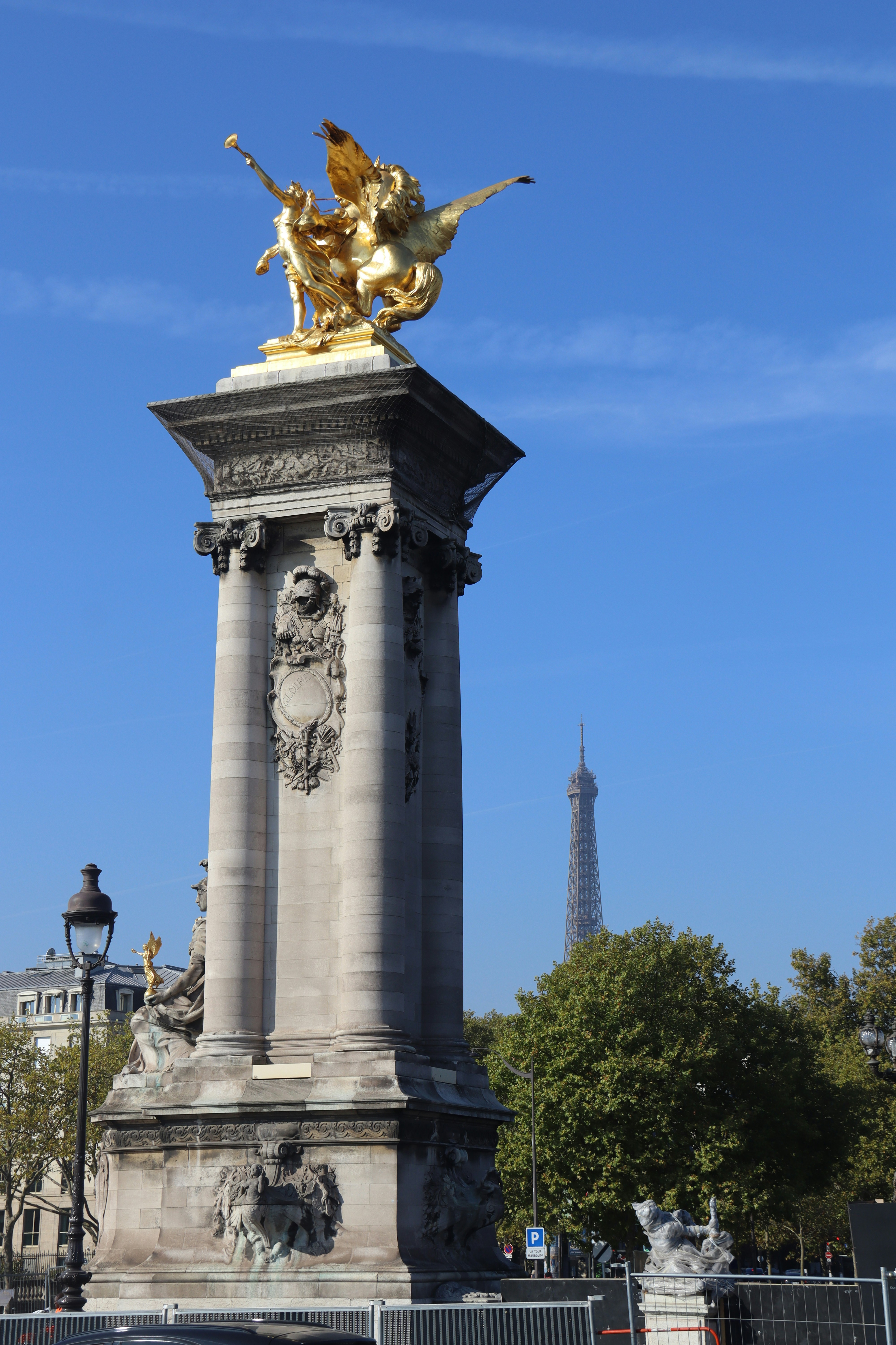 Golden sculpture atop stone pillar with eiffel tower background