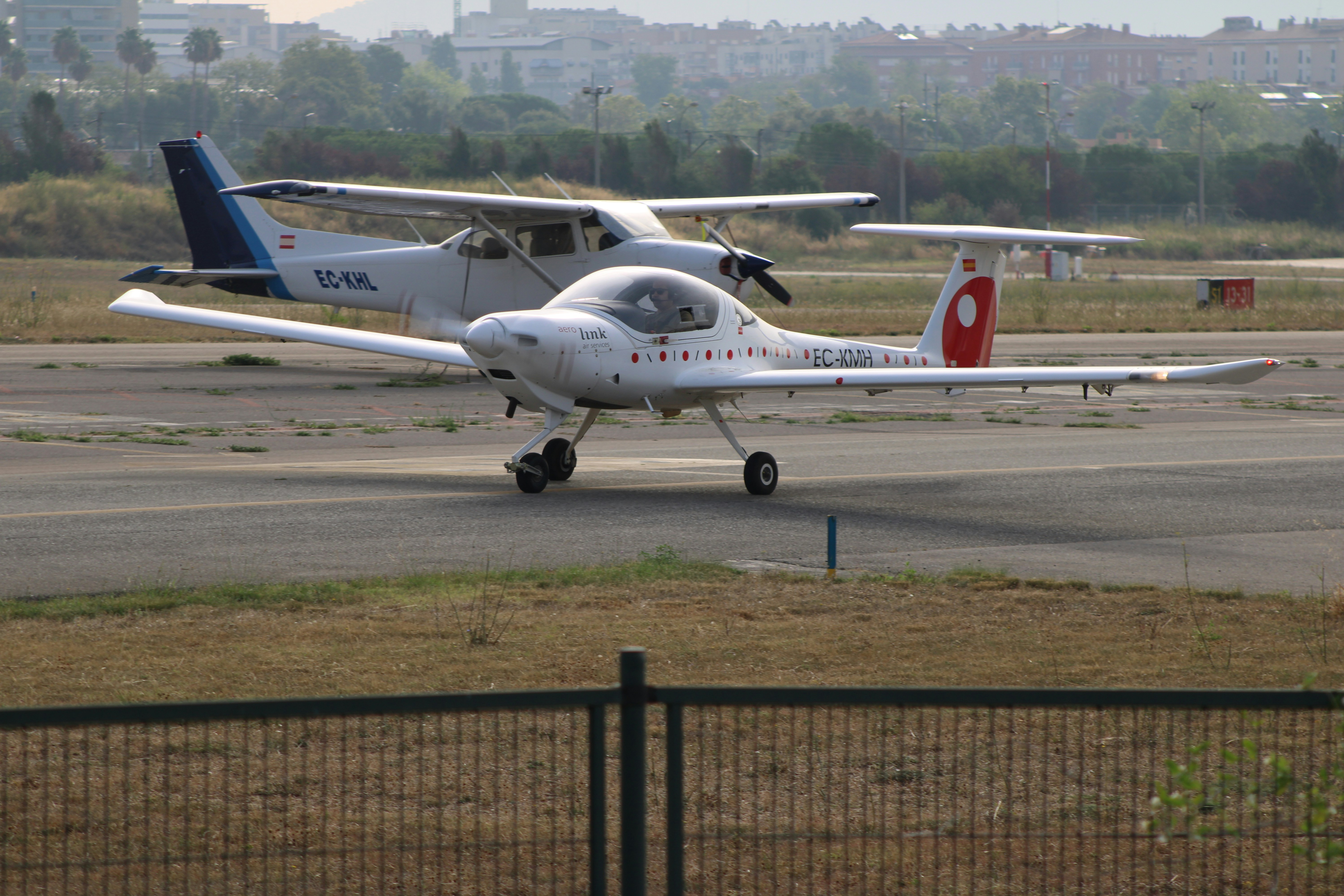 An electric aircraft taxis on a runway alongside a traditional plane, showcasing advancements in aviation technology.