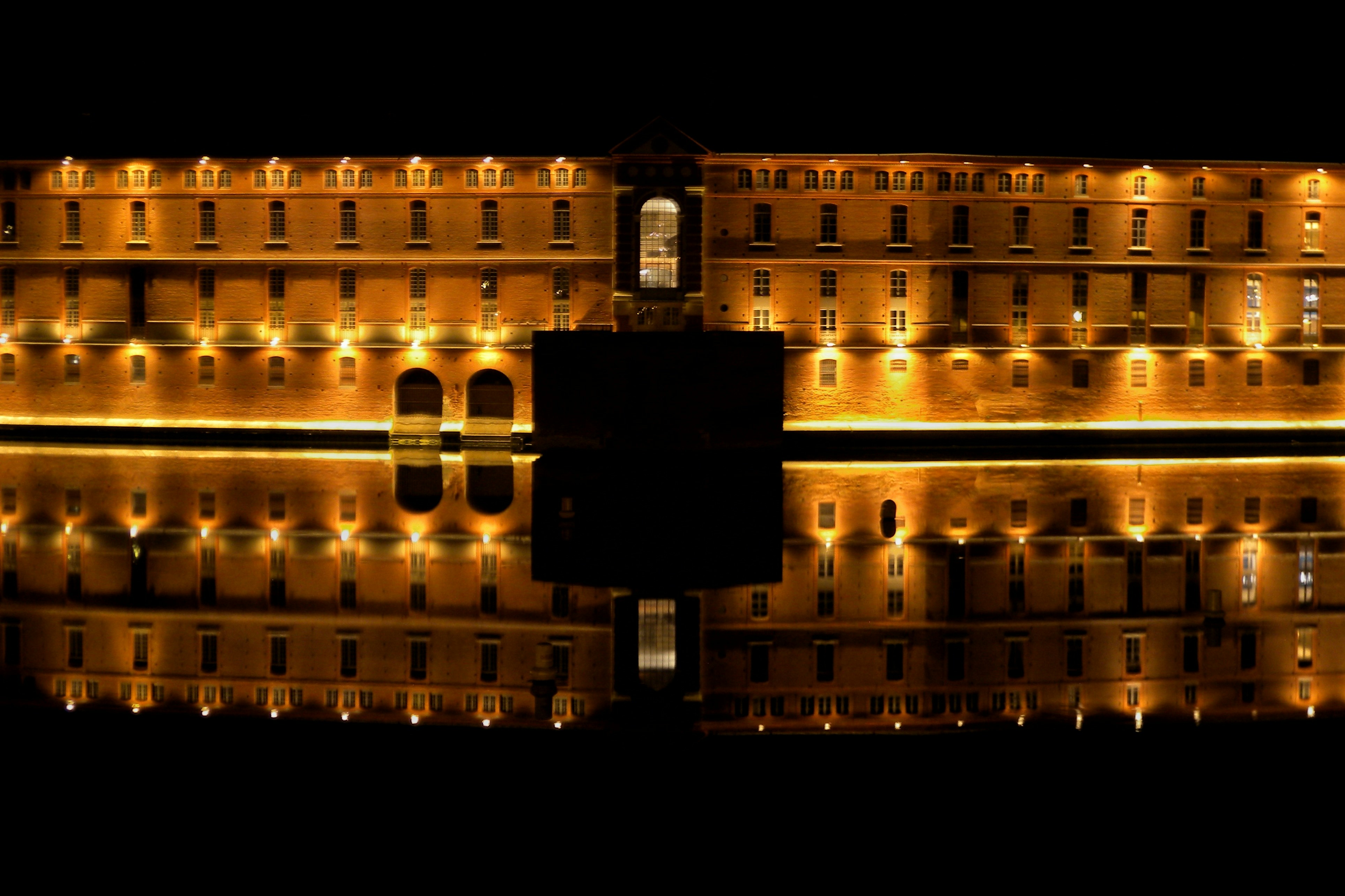 Illuminated building reflected in dark water at night