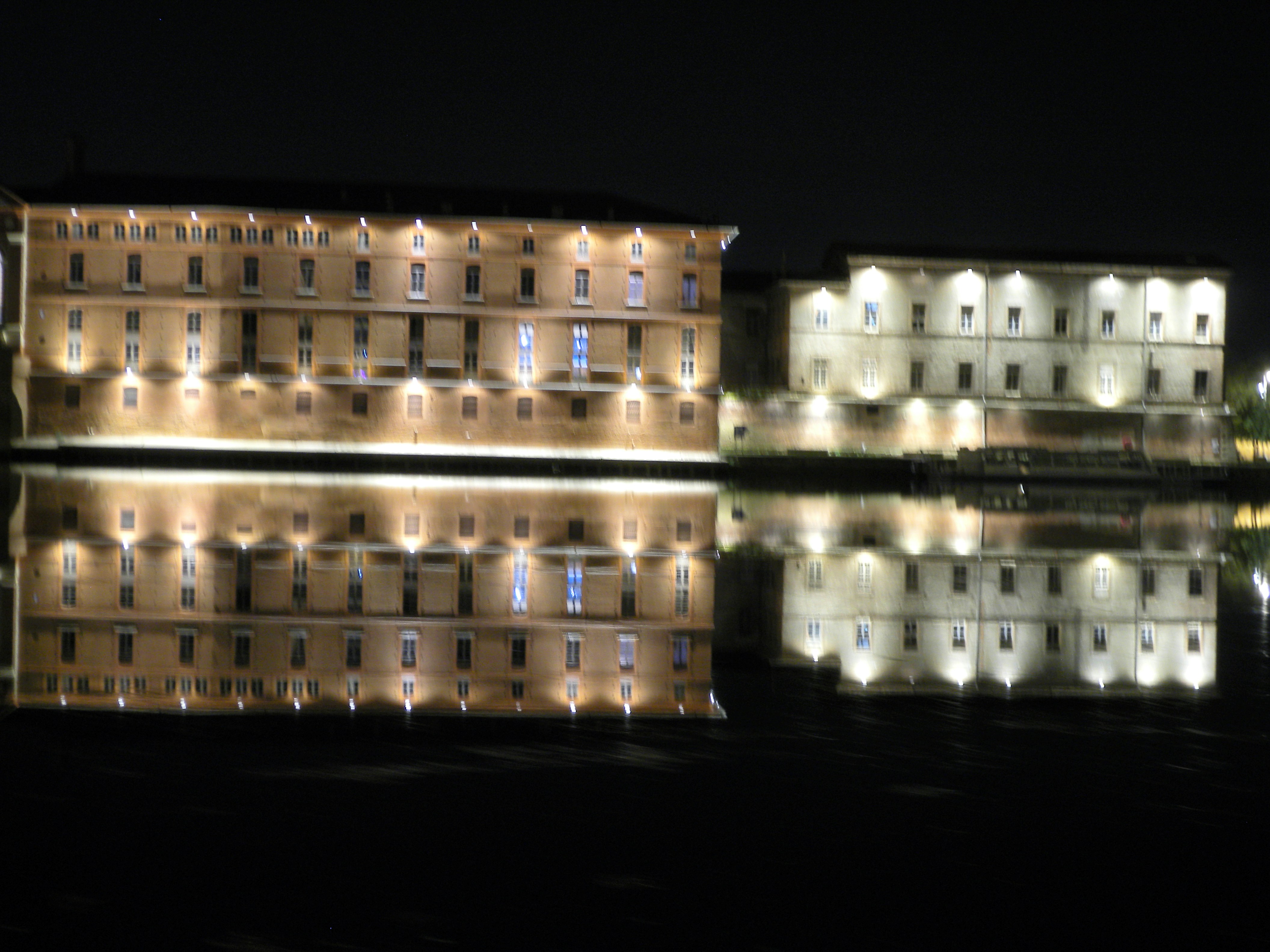 Buildings illuminated at night reflected in water