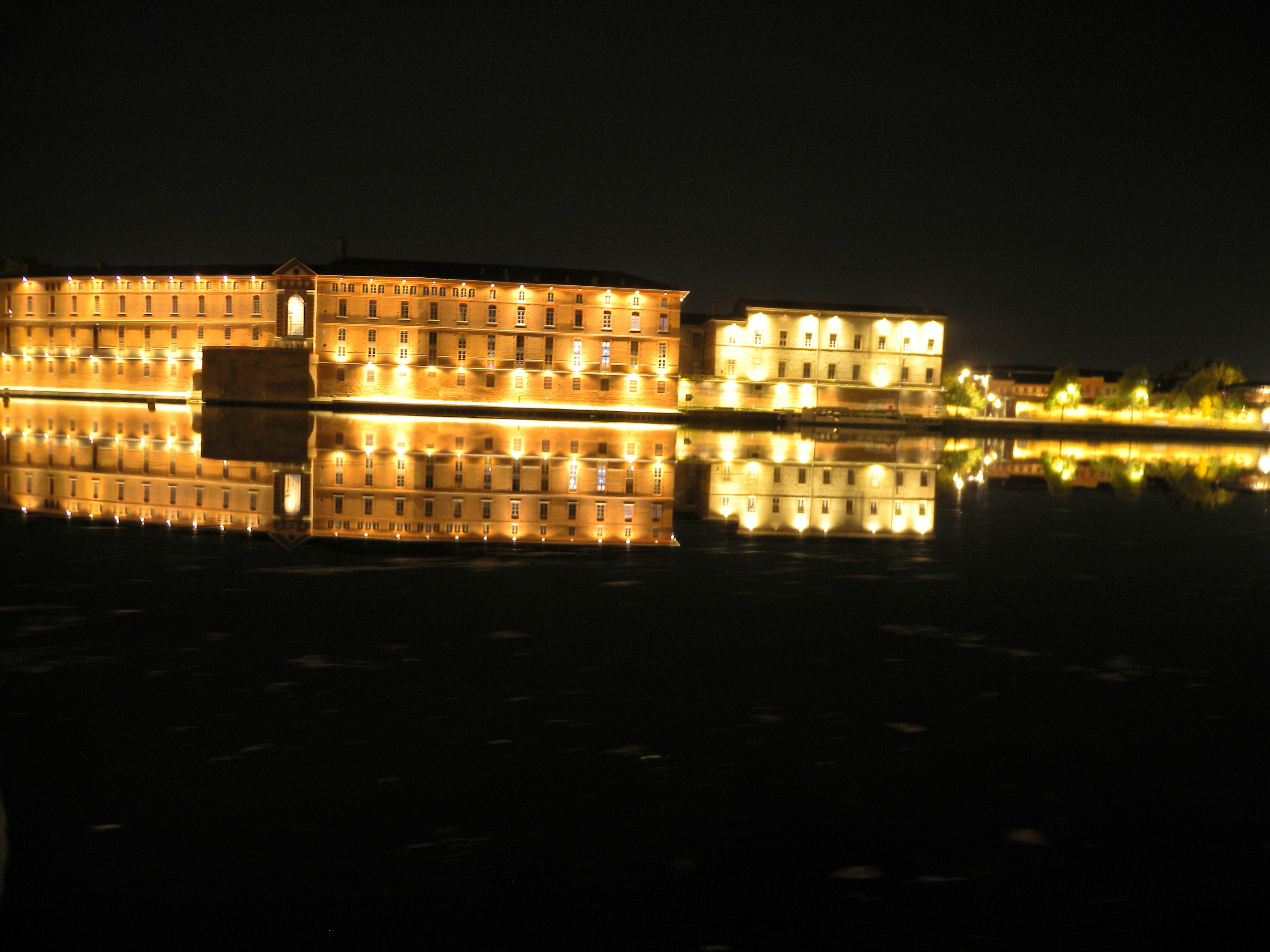 Illuminated building reflected in dark water at night