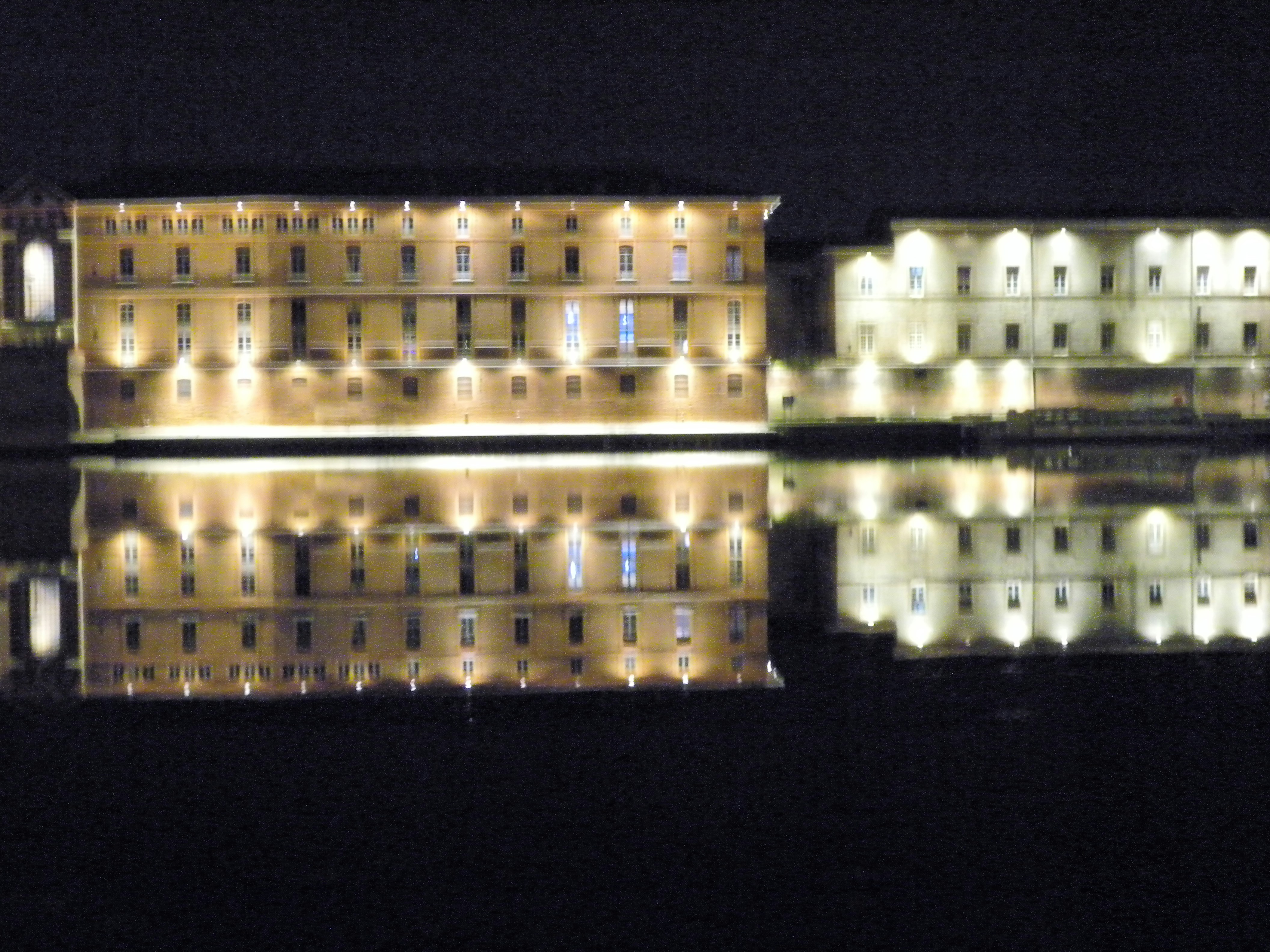 Buildings reflected in dark water at night.