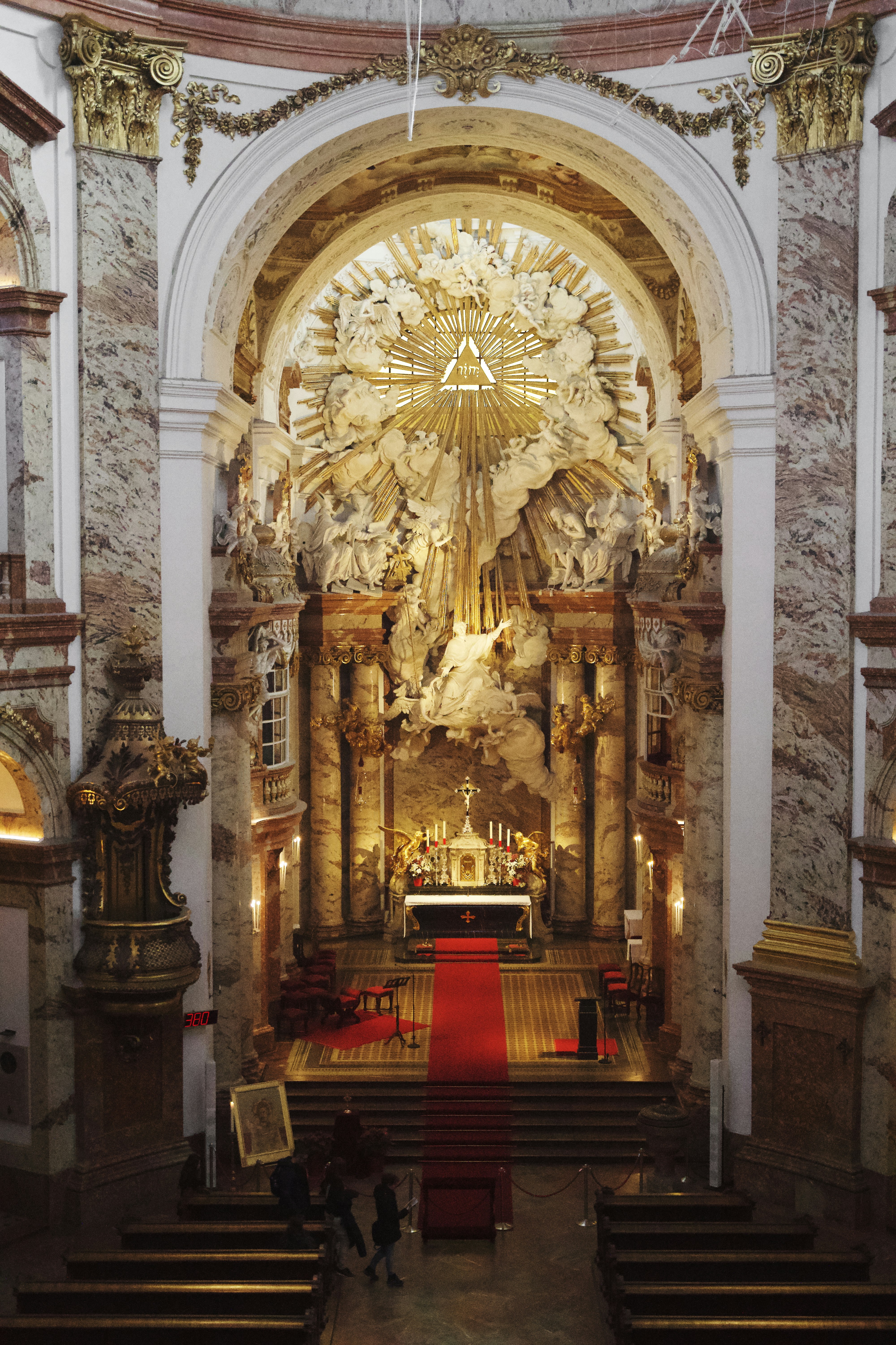 Sunday morning at the Karlskirche of Vienna. | Ornate church interior with altar and red carpet.