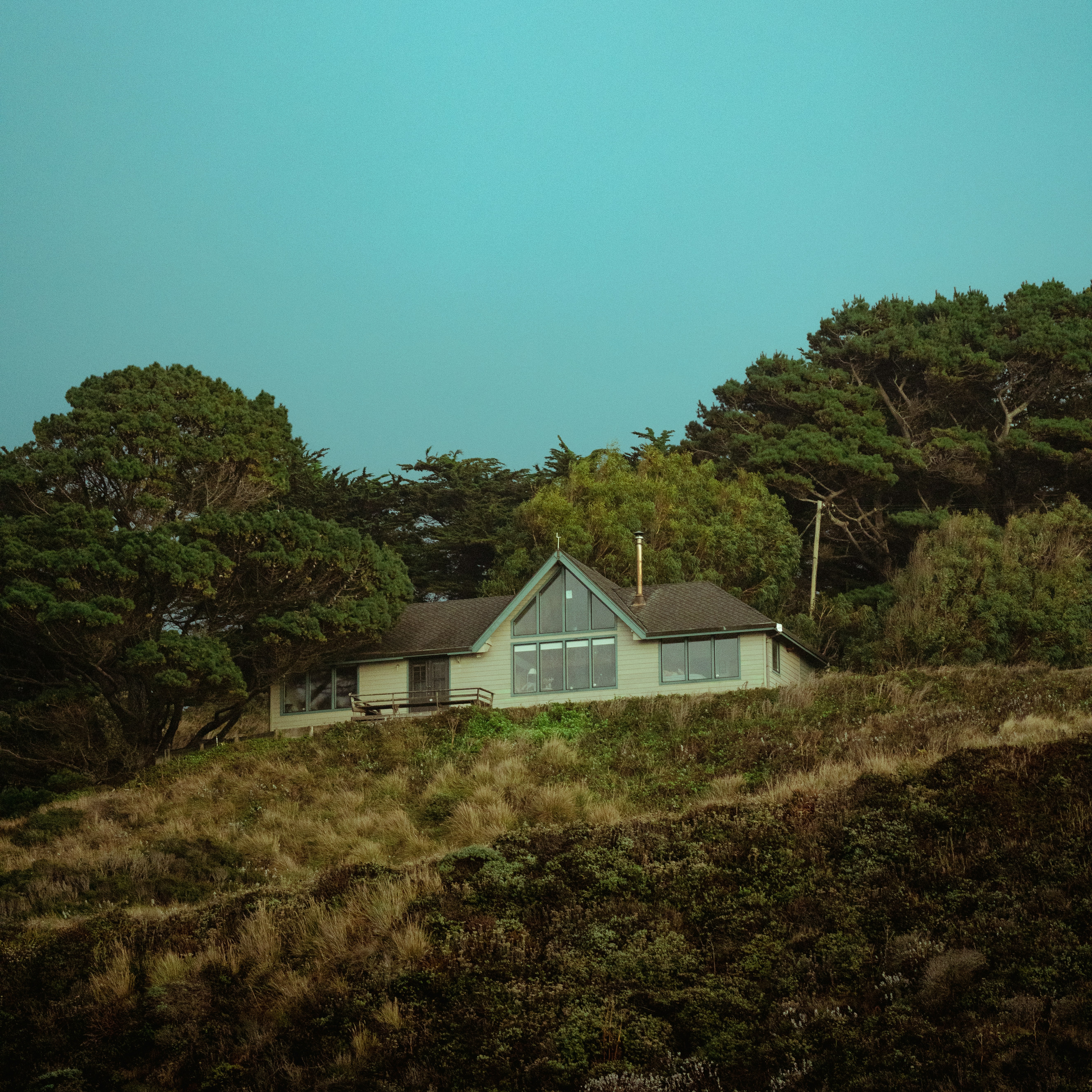 A modern house nestled on a grassy hill.