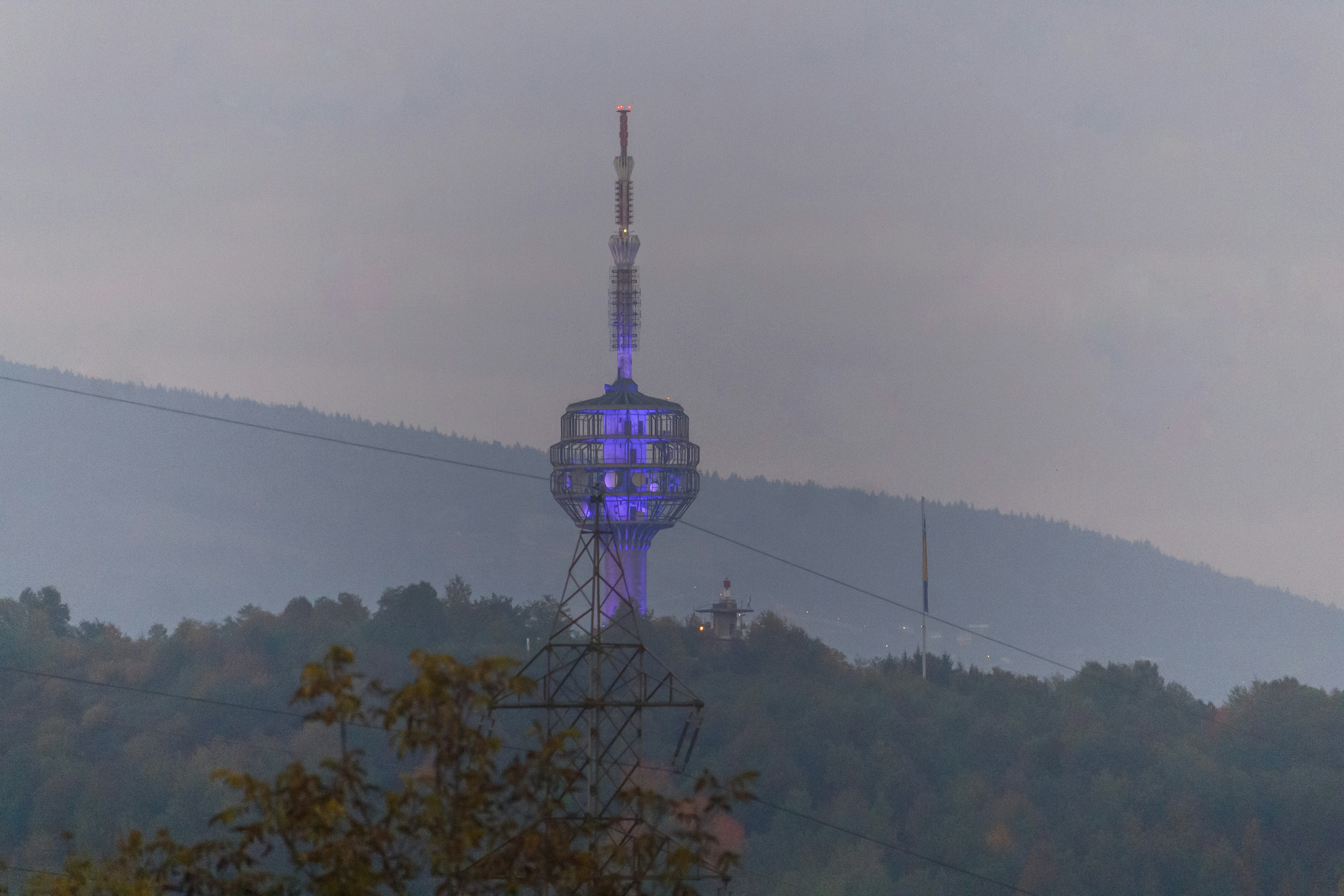 A tall tower illuminated with purple lights at dusk