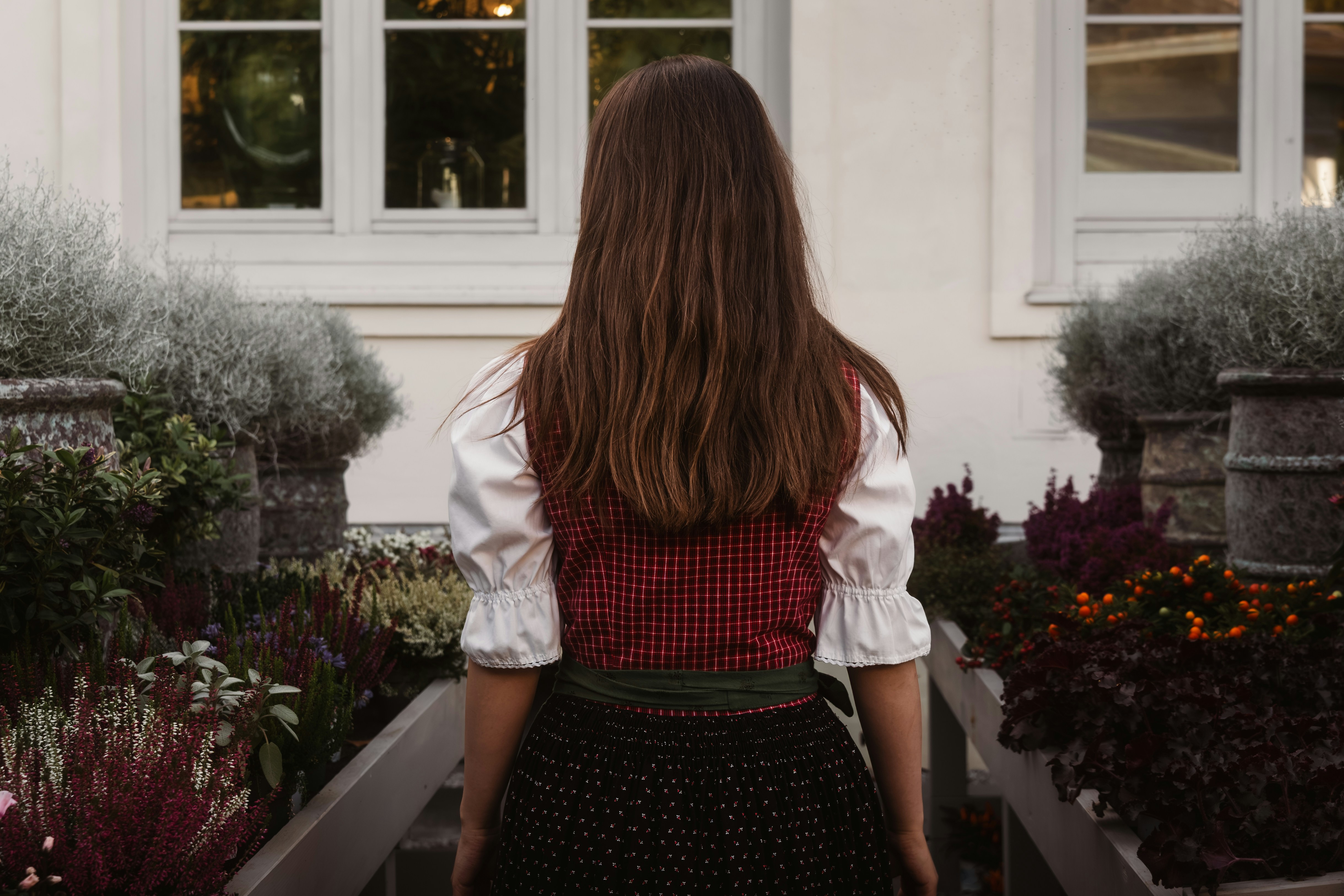 Rear view in traditional dress among autumn plants | Young girl in traditional dress walking towards building