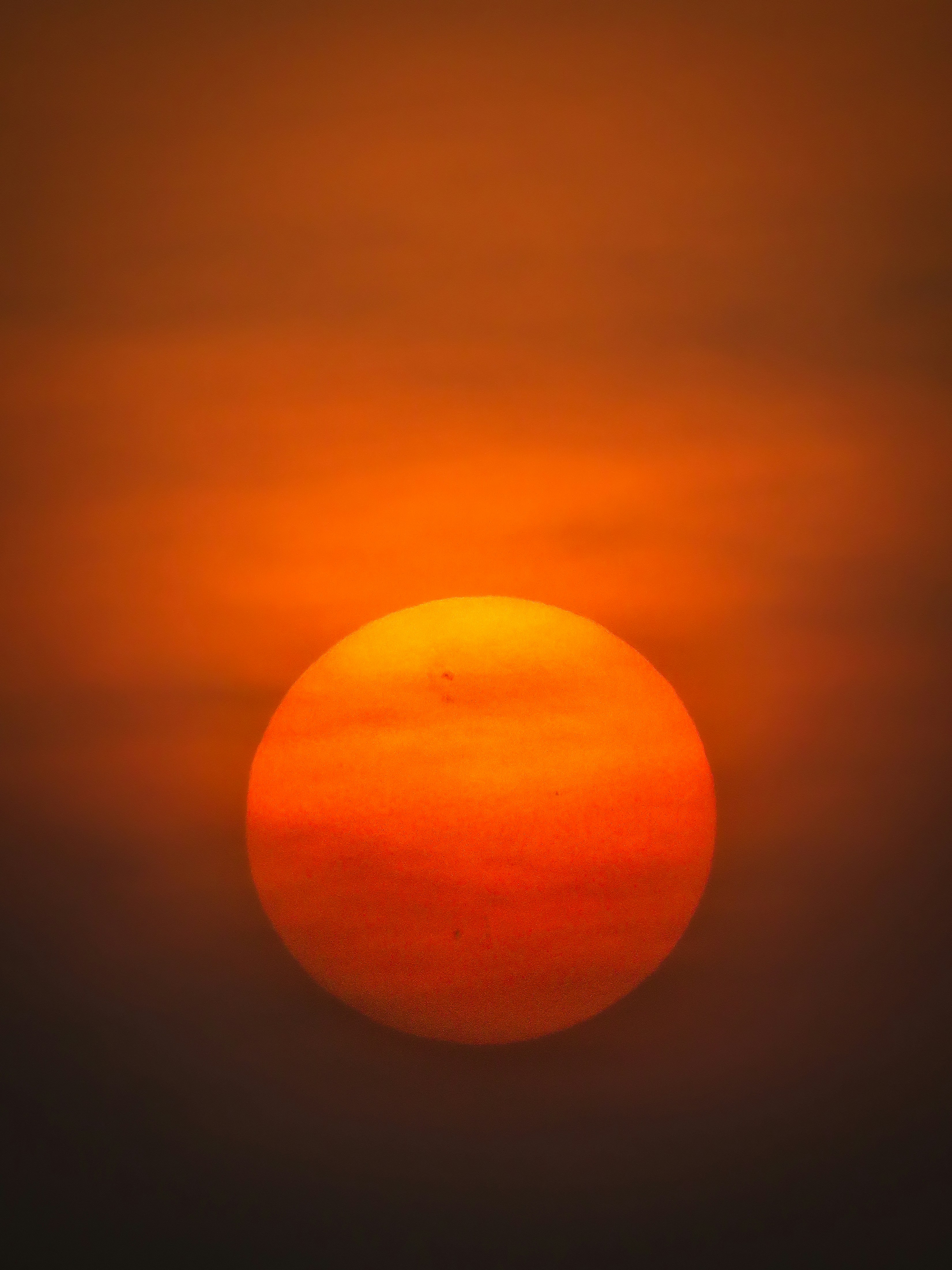 A large, bright sun setting over a hazy horizon.