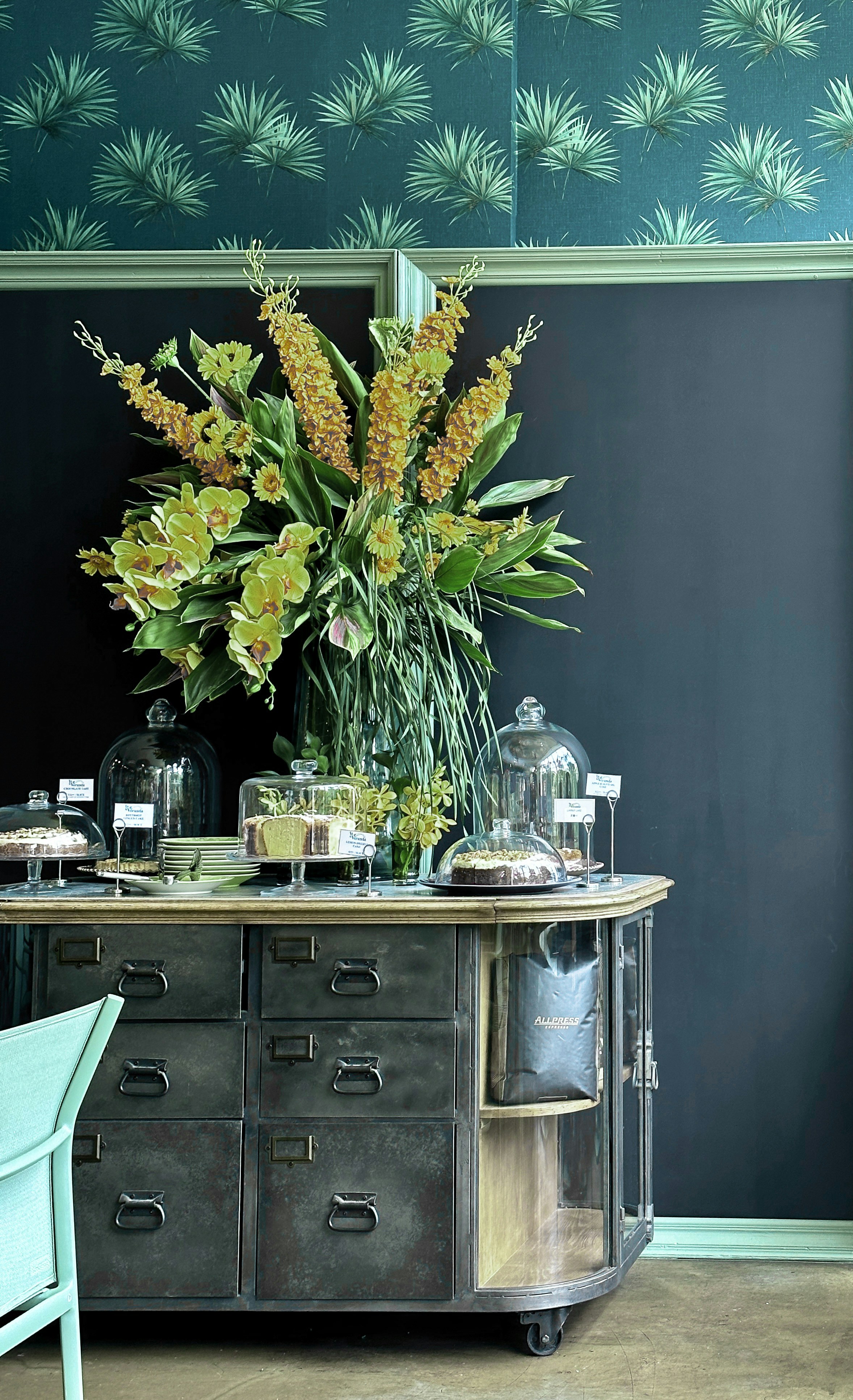 A large floral arrangement sits on a vintage cabinet.