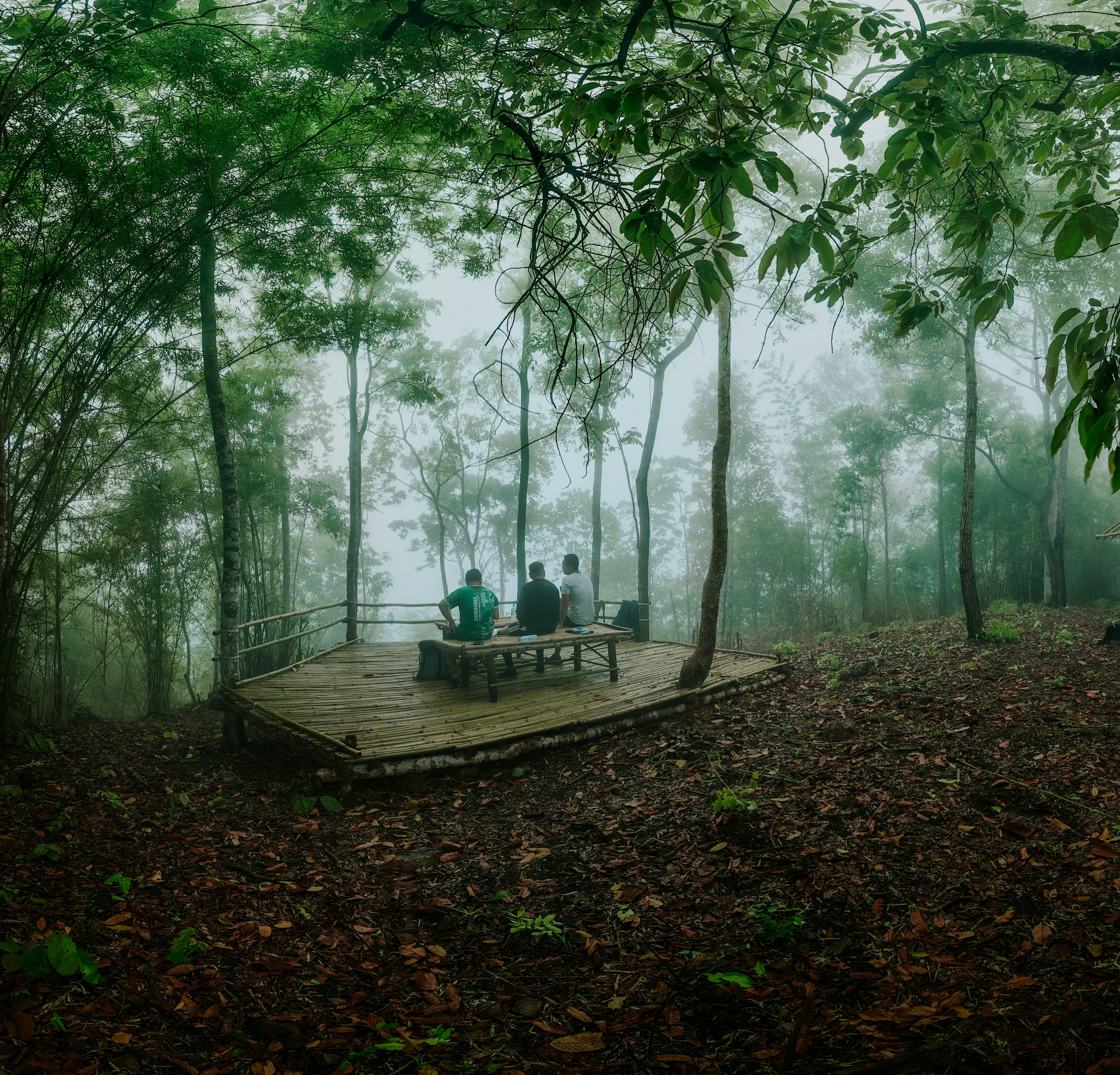 Mlech Trail Kampot ,Cambodia | People sitting on a wooden platform in a foggy forest.