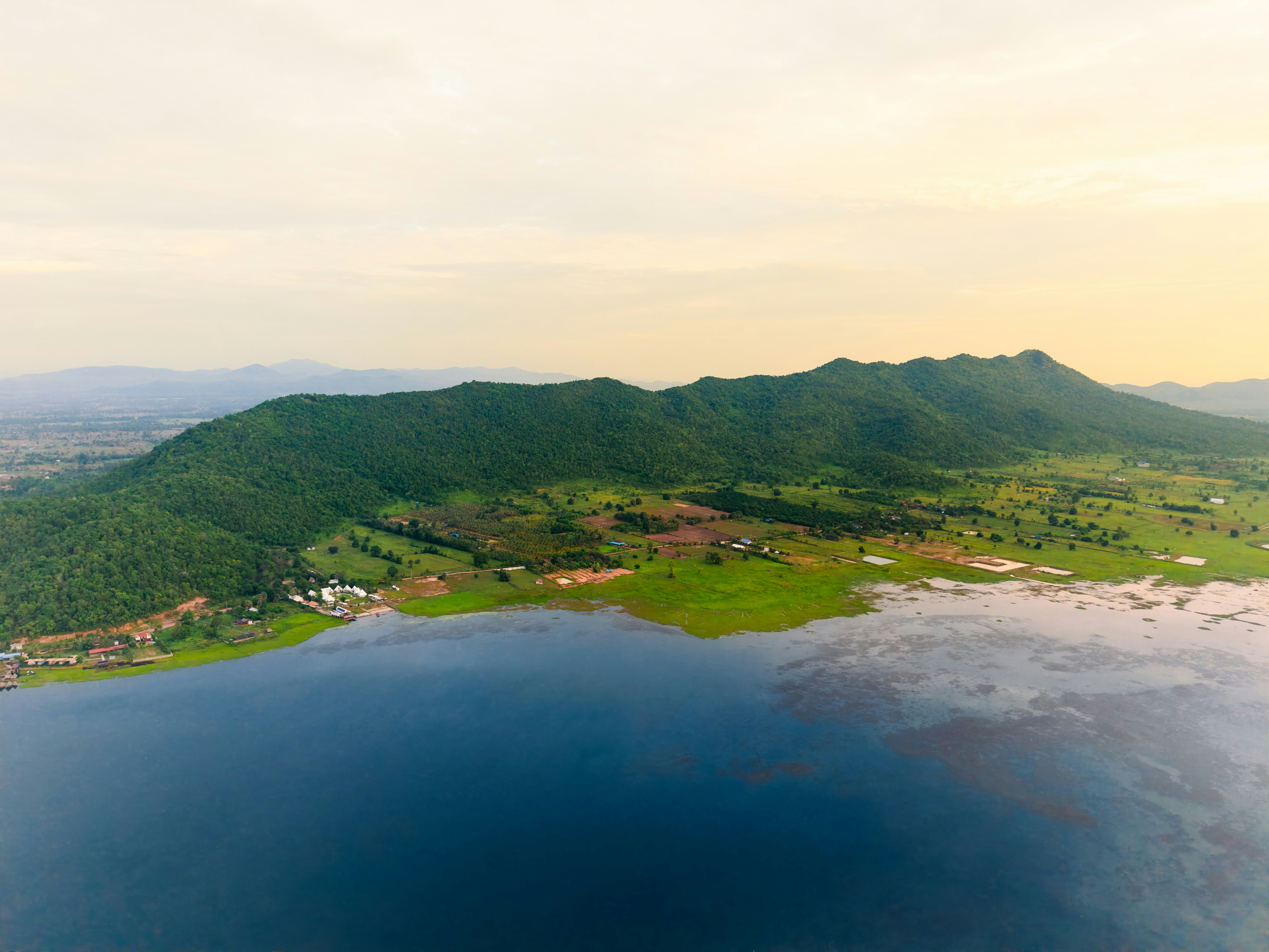 Mlech Trail Kampot, Cambodia | Green hills border a large blue lake under sky.