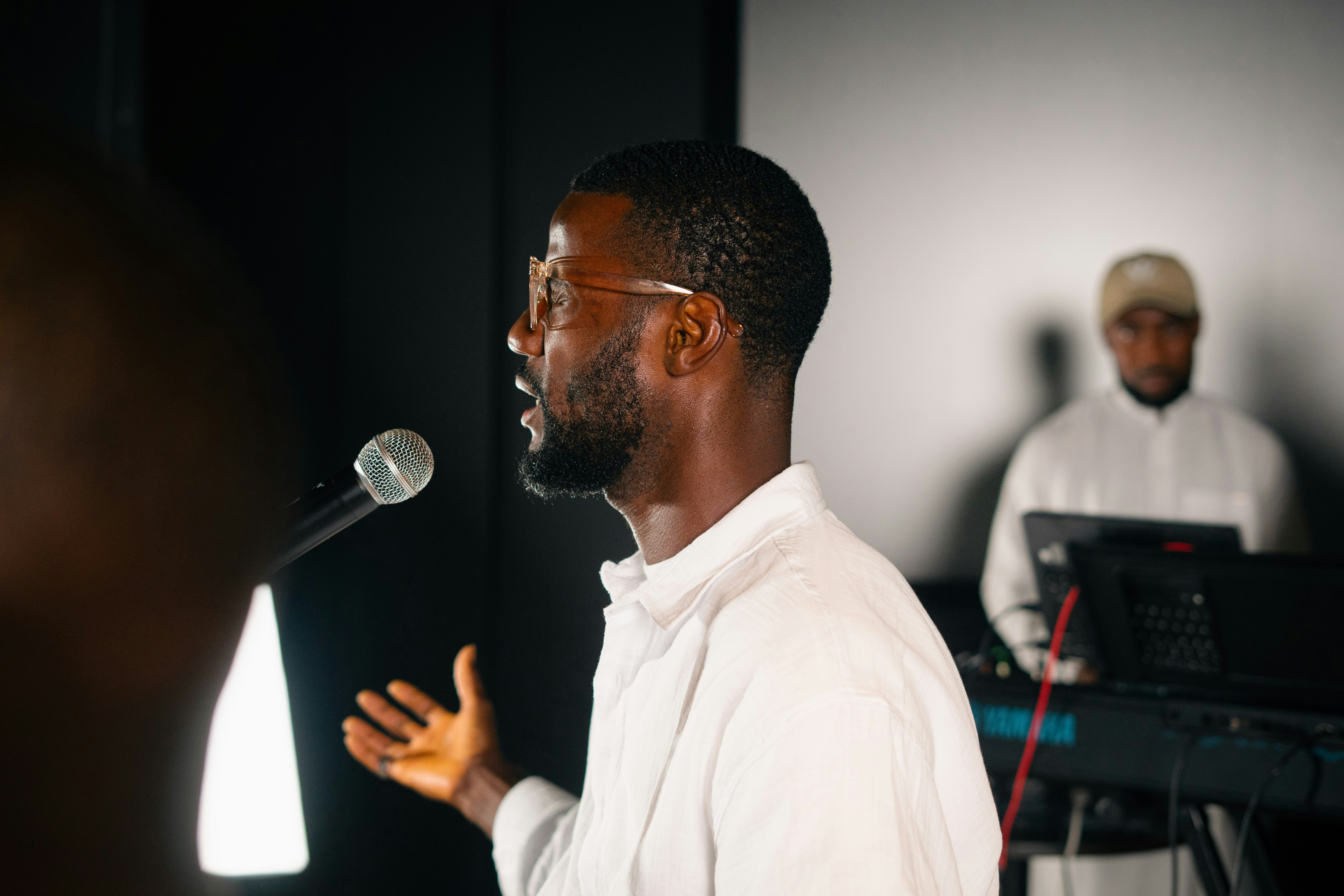 Man speaking into a microphone with another man behind him.