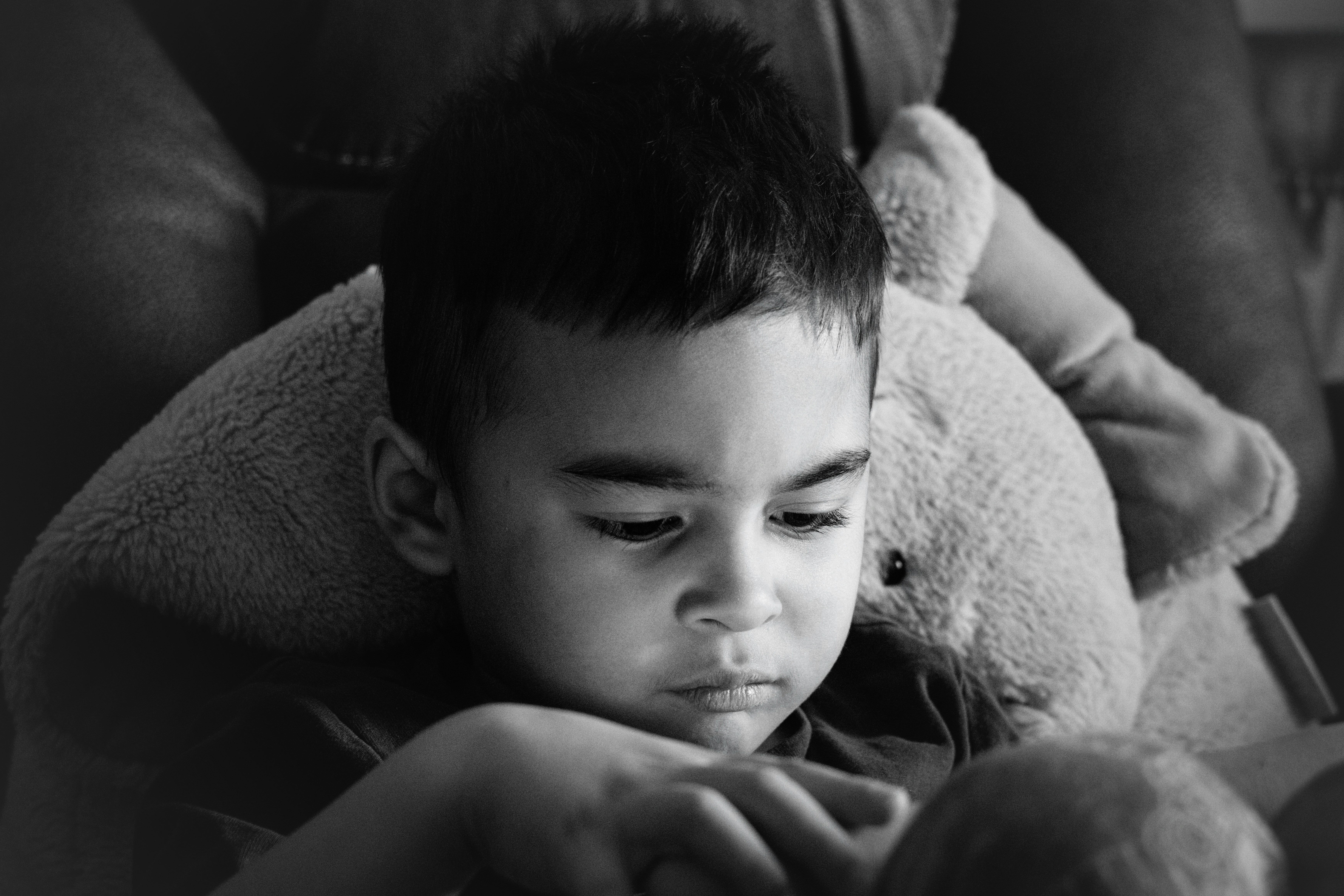 Young boy holding a stuffed animal in black and white.