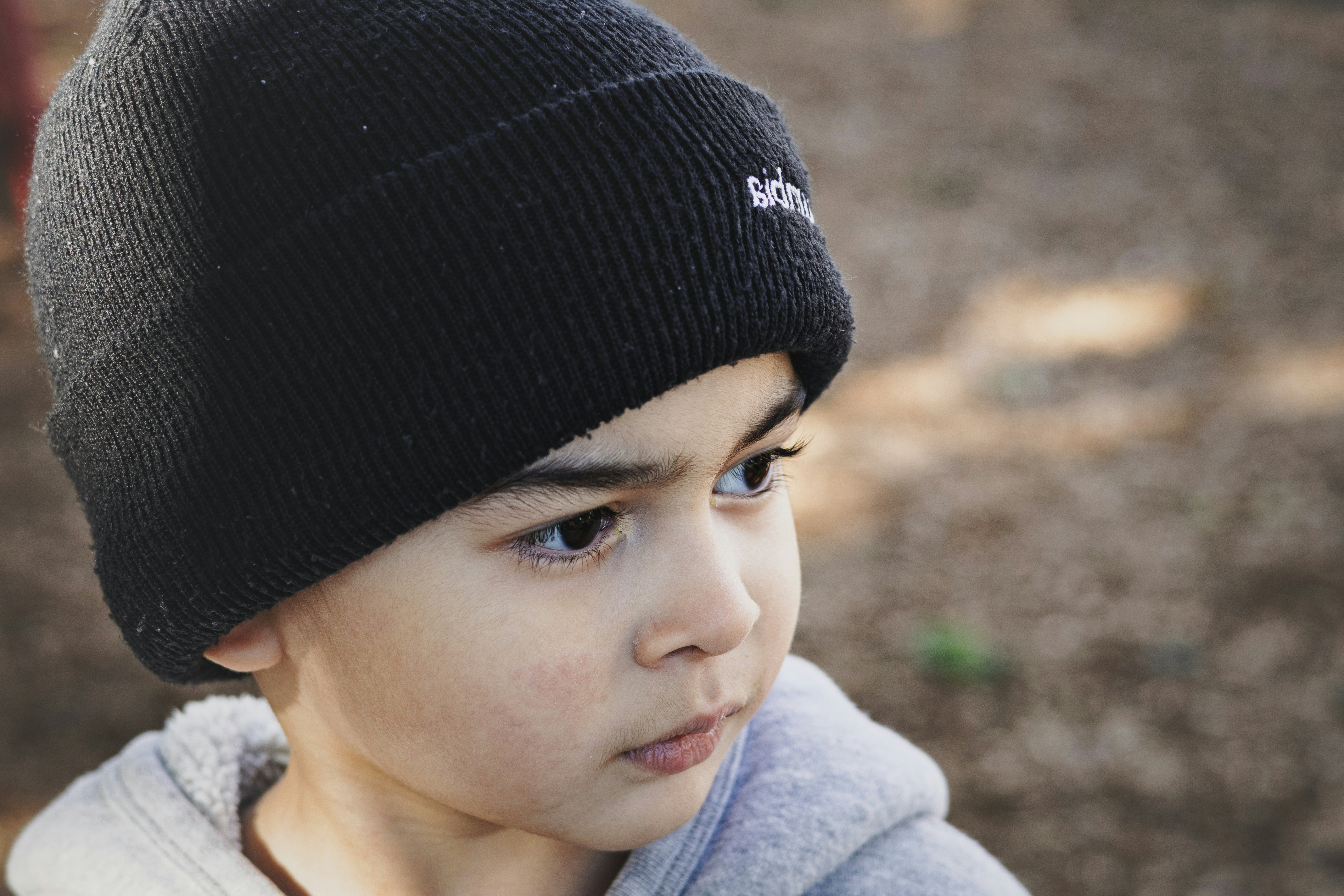 A young boy wearing a black beanie and hoodie.