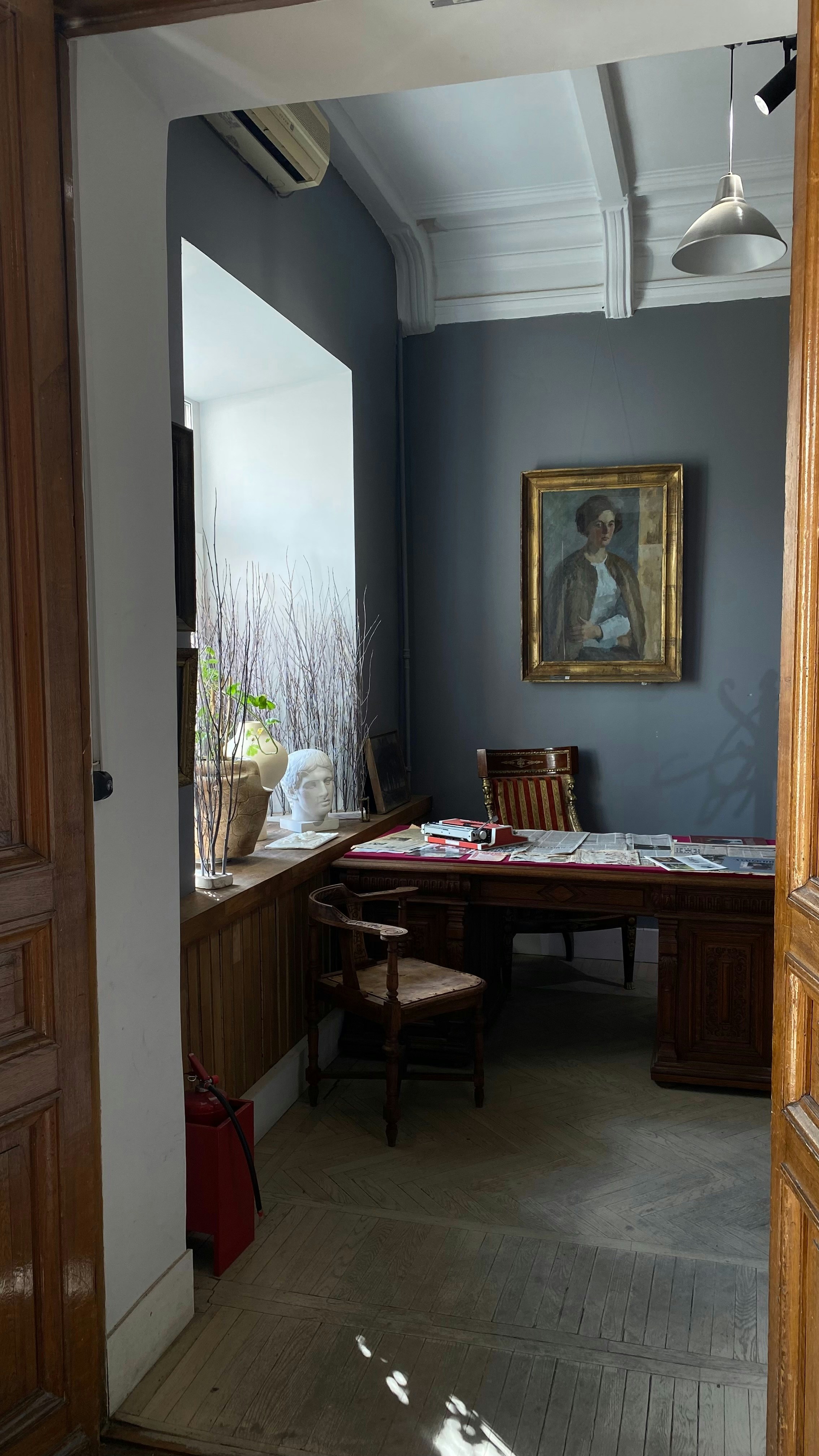 An office with a desk, chairs, and a painting.