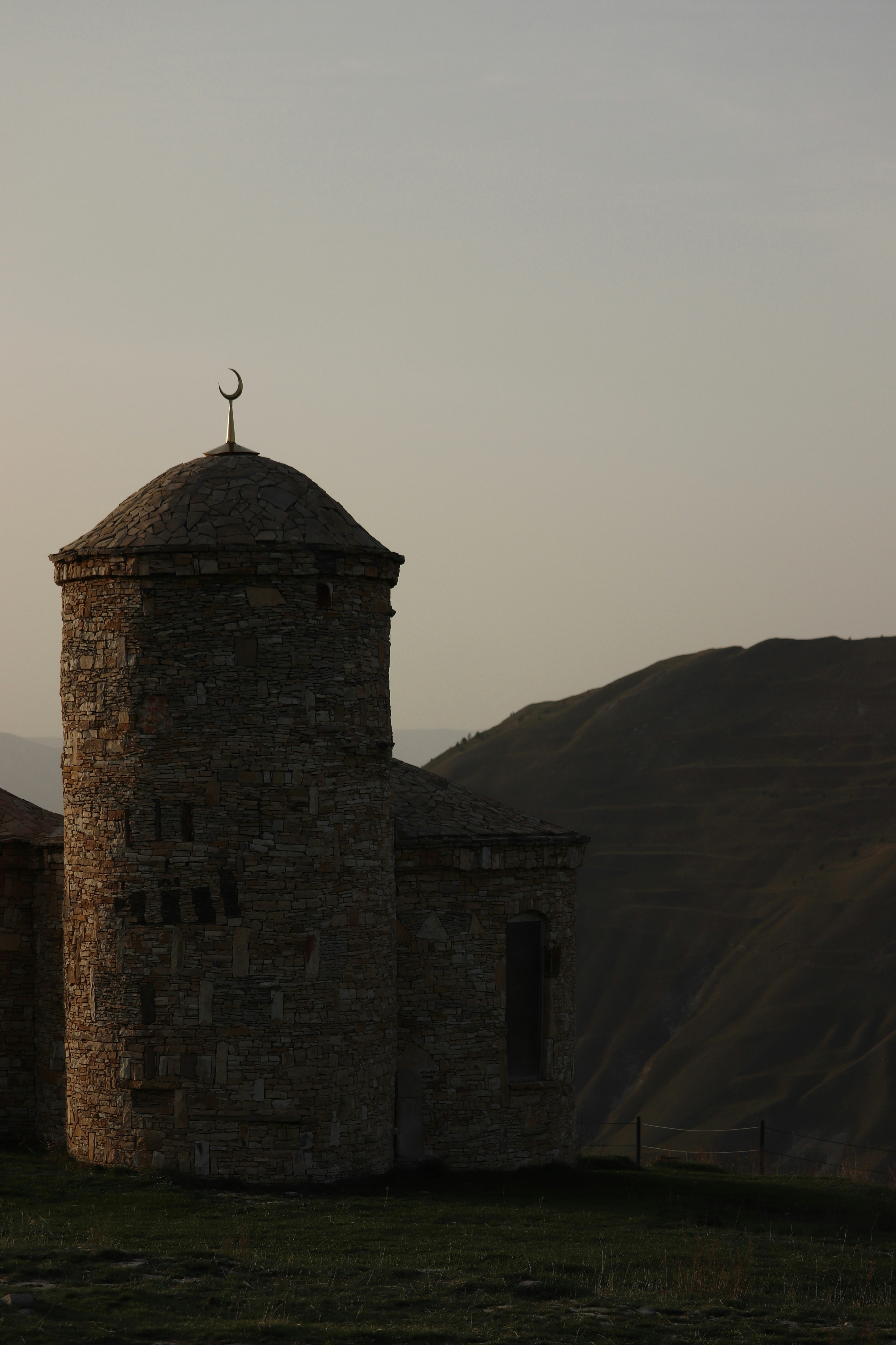 Stone tower with crescent moon symbol on hill