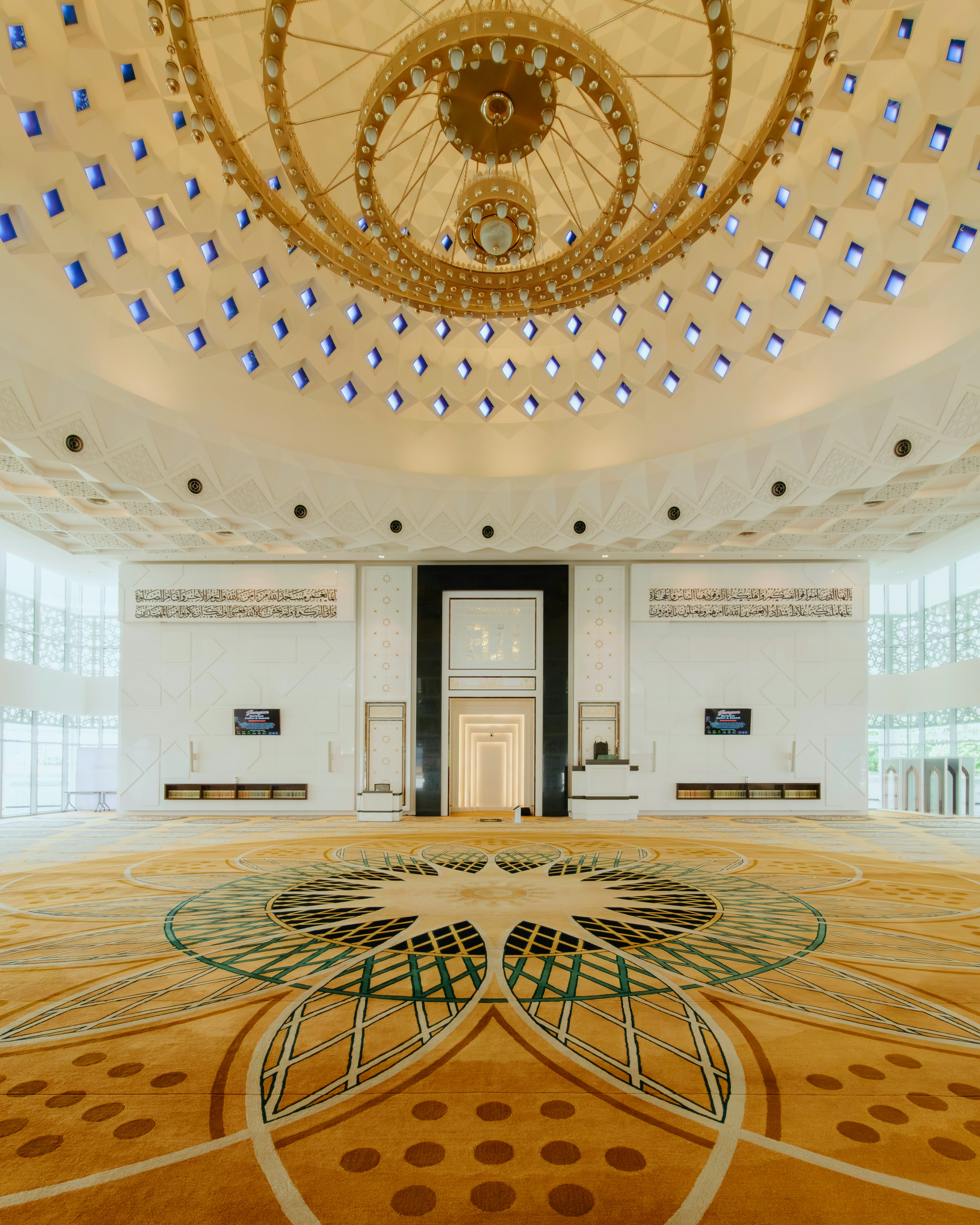 Intricate interior of a mosque featuring a grand chandelier and ornate ceiling design, showcasing the architectural elegance and spiritual ambiance.