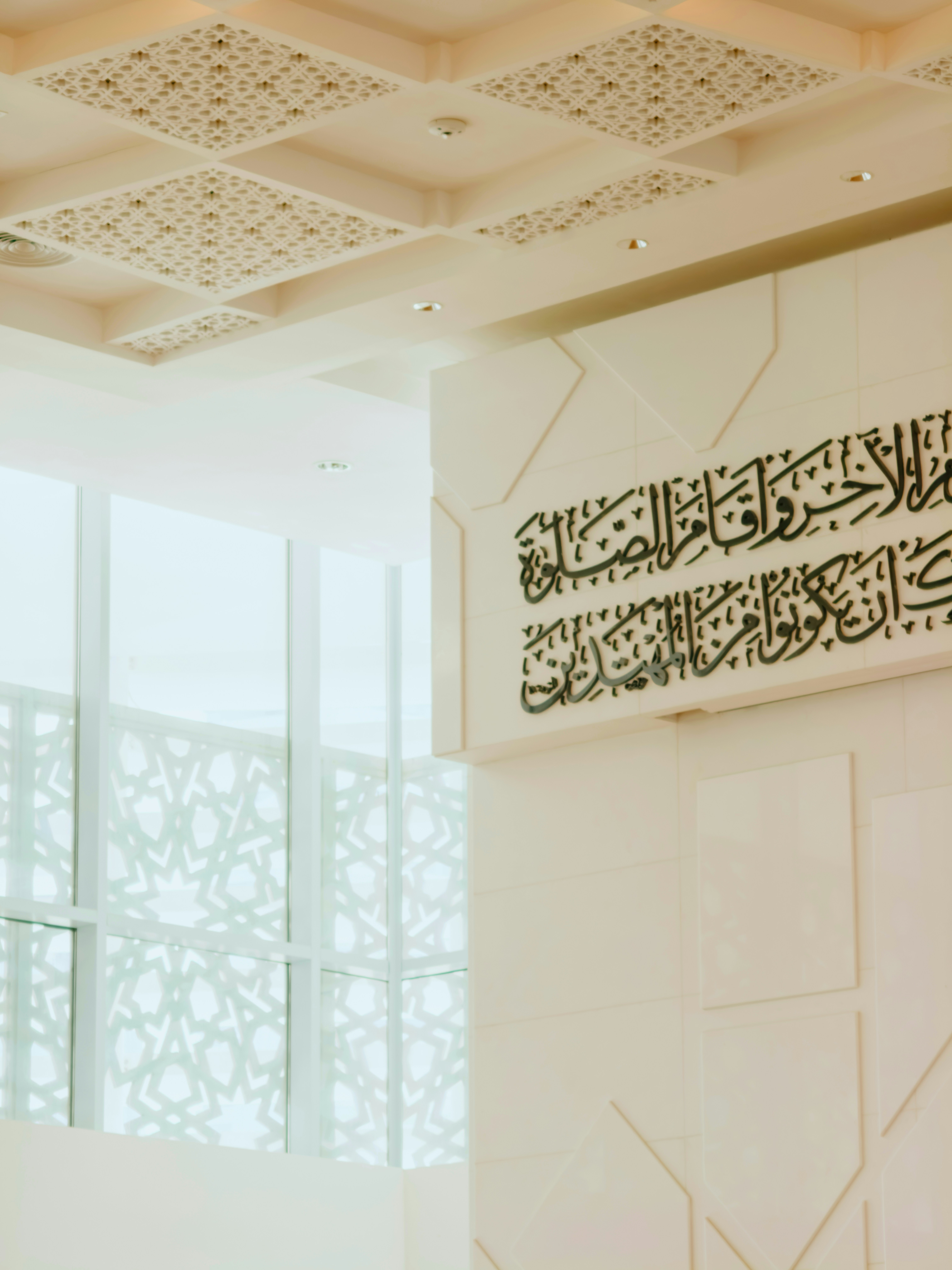 Intricate Arabic calligraphy adorns a modern architectural interior, blending cultural heritage with contemporary aesthetics.